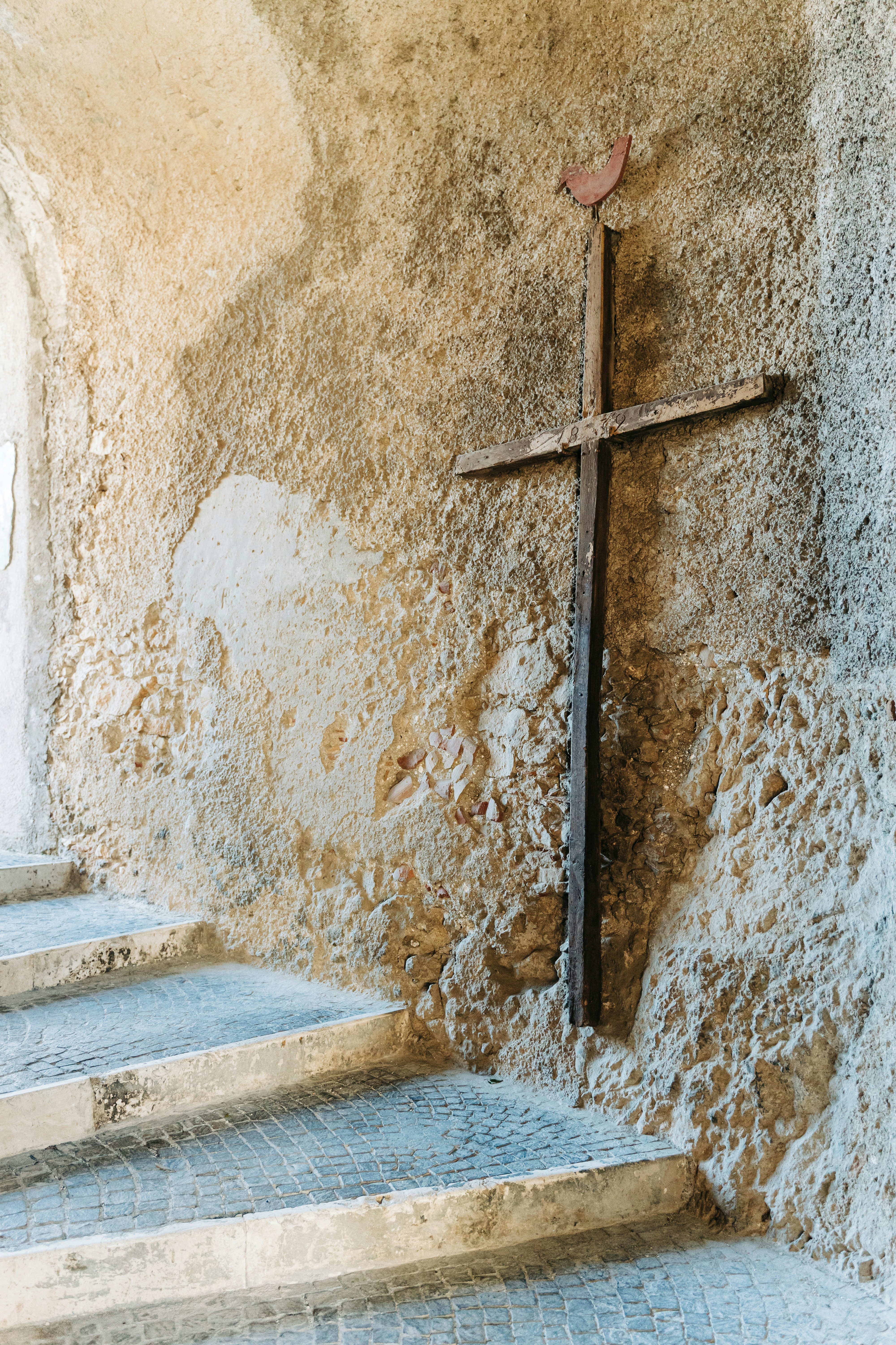 An iron cross on a sandstone wall in Cervara di Roma, Italy