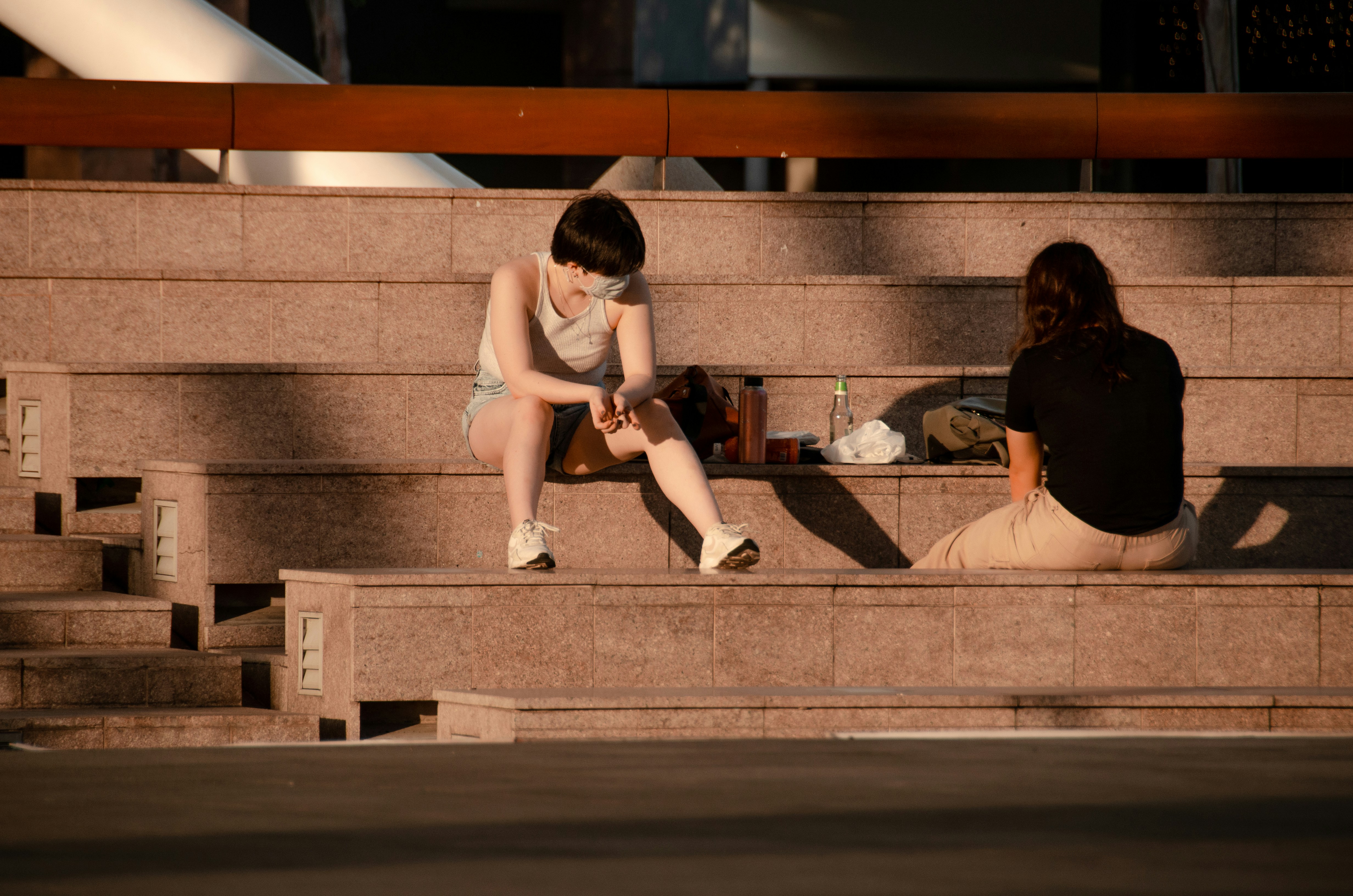 Sunlit Pause on Urban Steps: A Quiet Moment Between Figures
