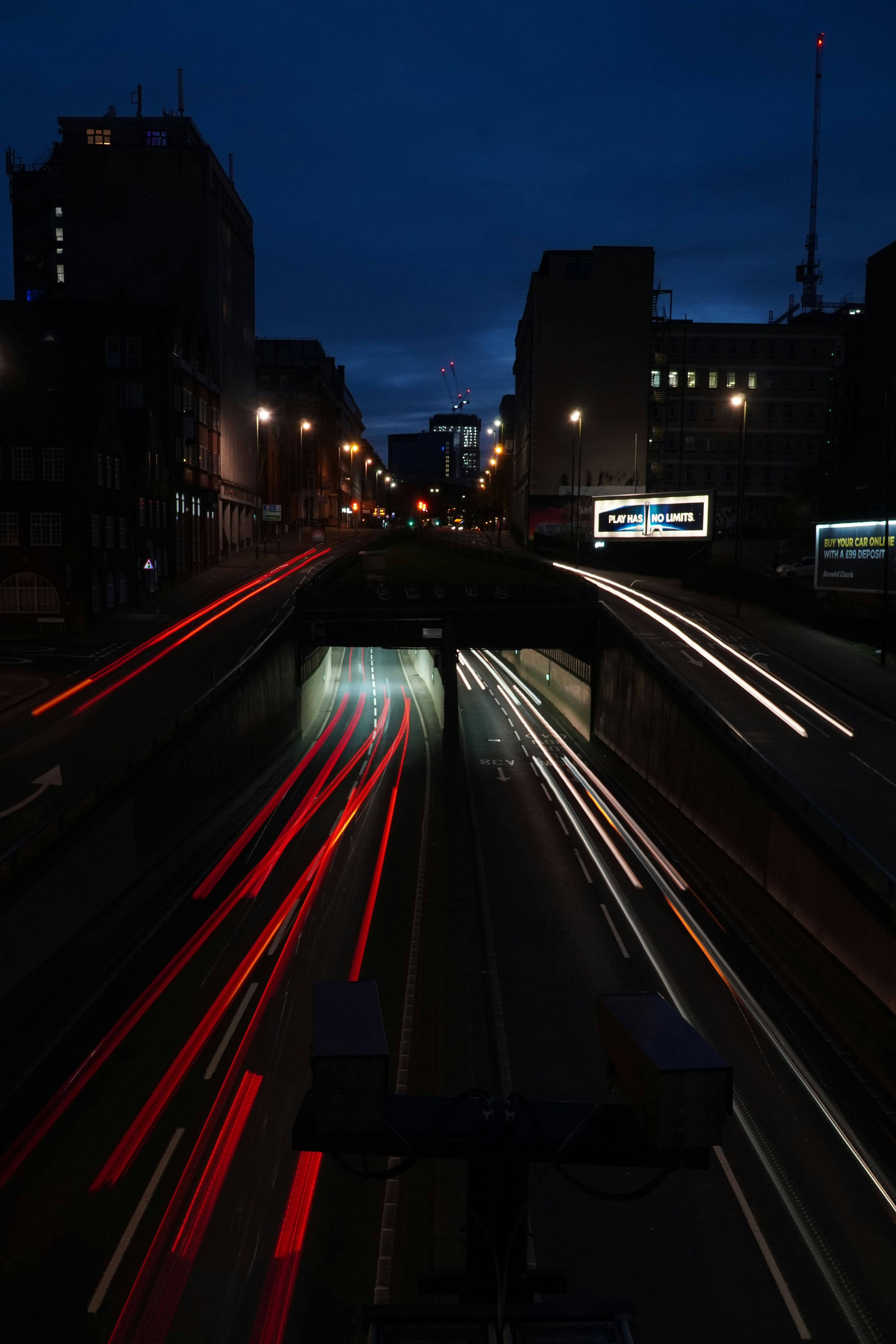 Long exposure shot capturing the dynamic flow of traffic through an urban tunnel at dusk, with vibrant streaks of light illuminating the scene.
