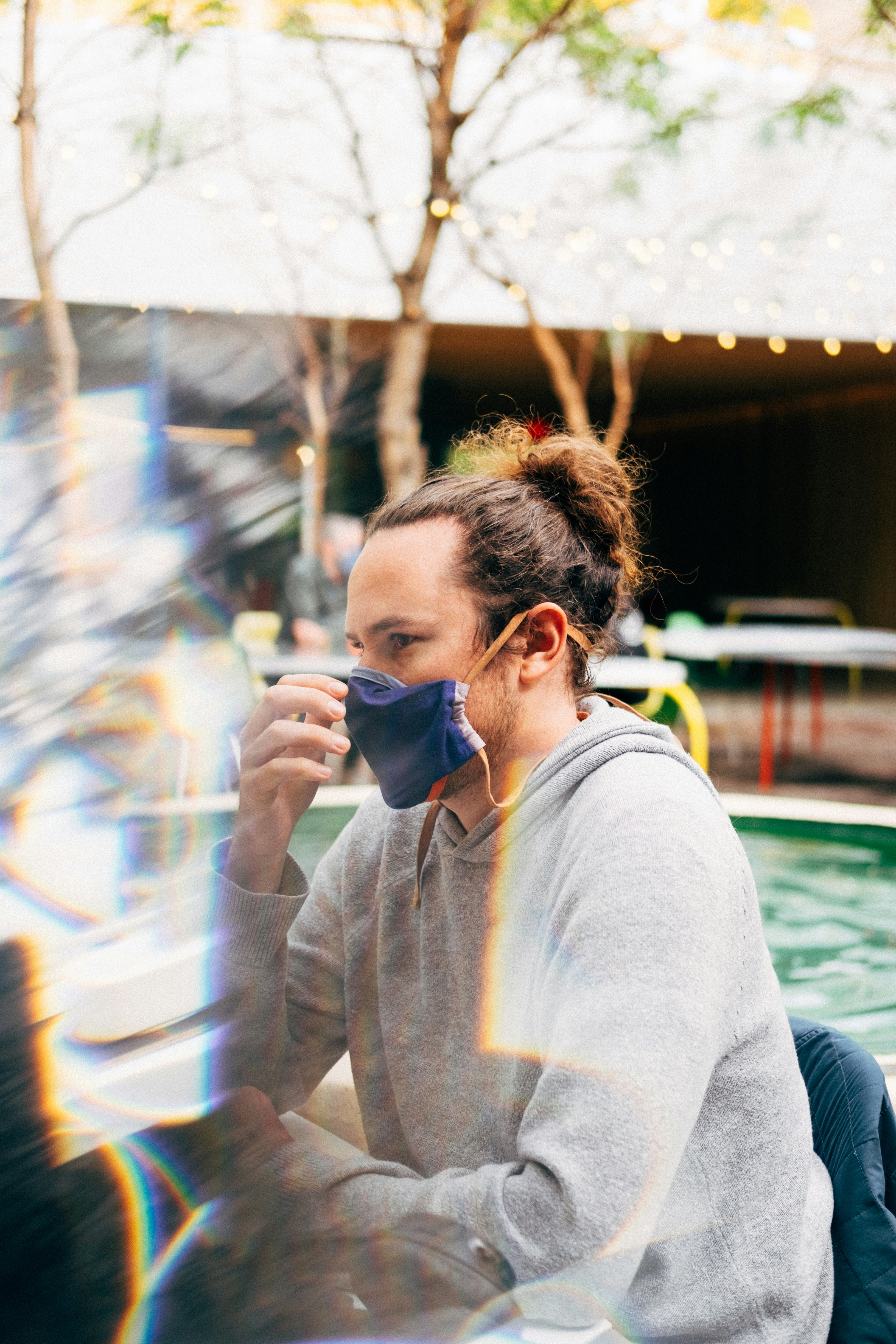 Prismatic Pause: A Masked Portrait by a Courtyard Pool