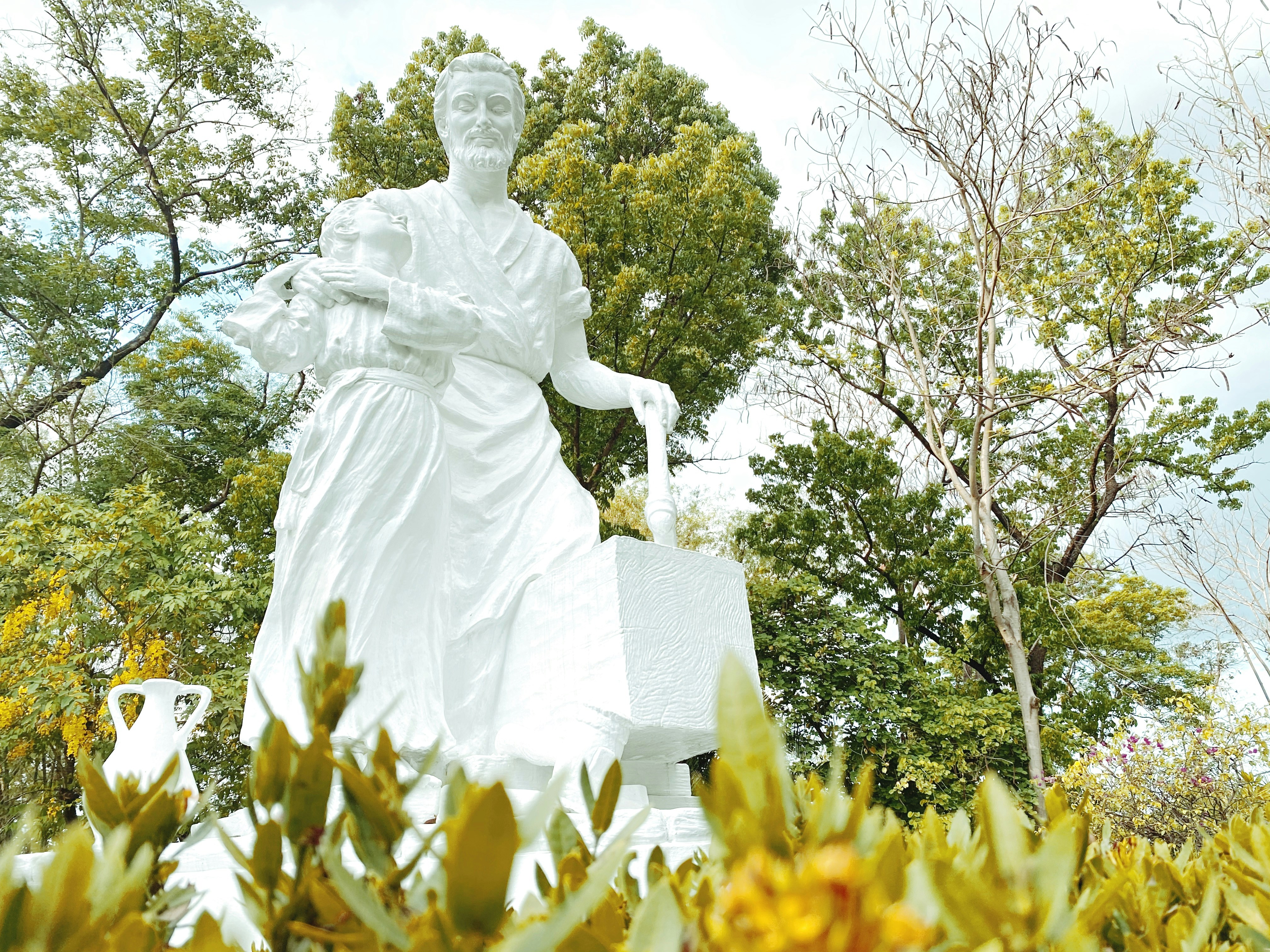 White Sentinel in a Quiet Park: A Classical Figure Beneath Spring Canopy