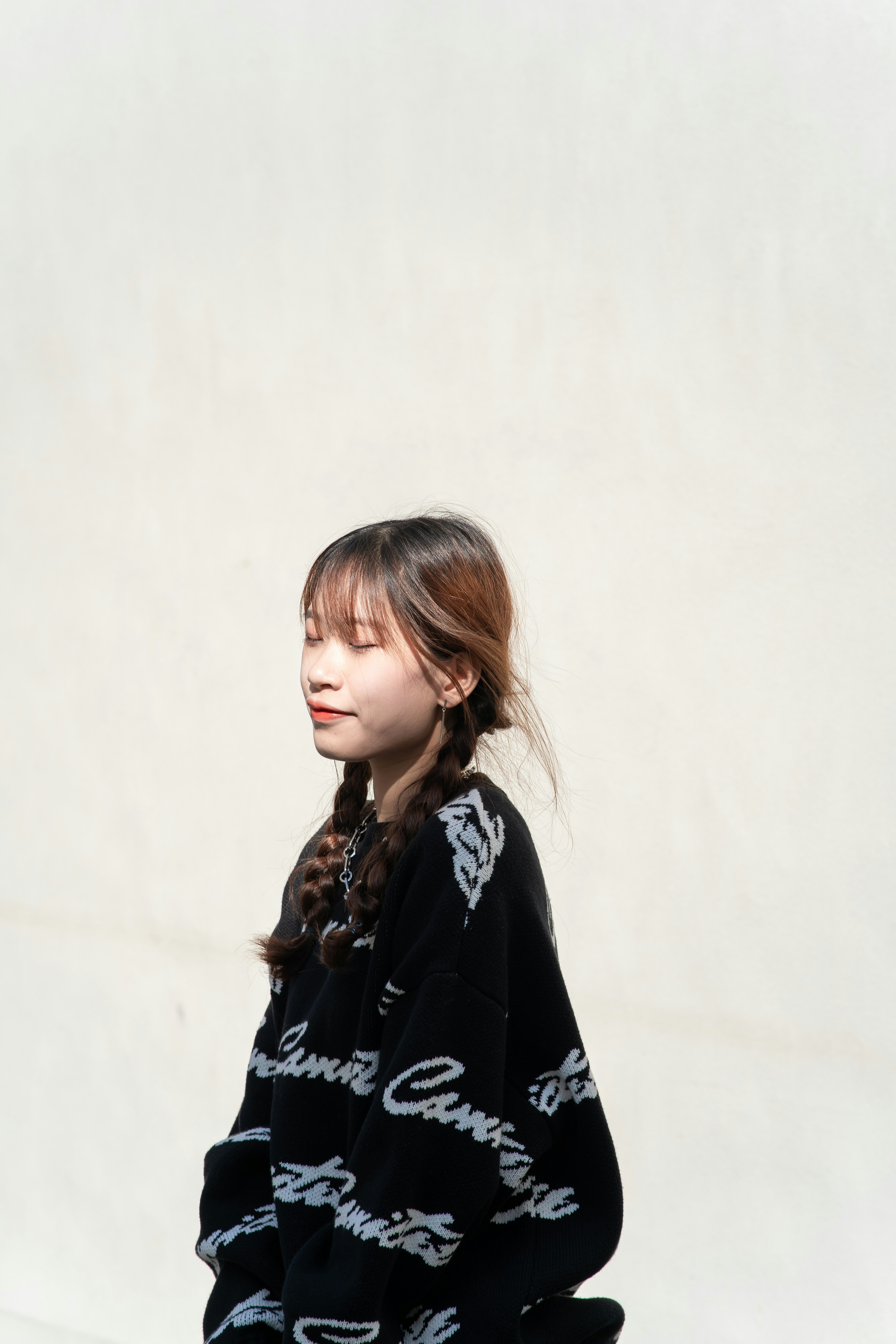 Braids in Sunlight: A Minimal Portrait Against a Pale Wall