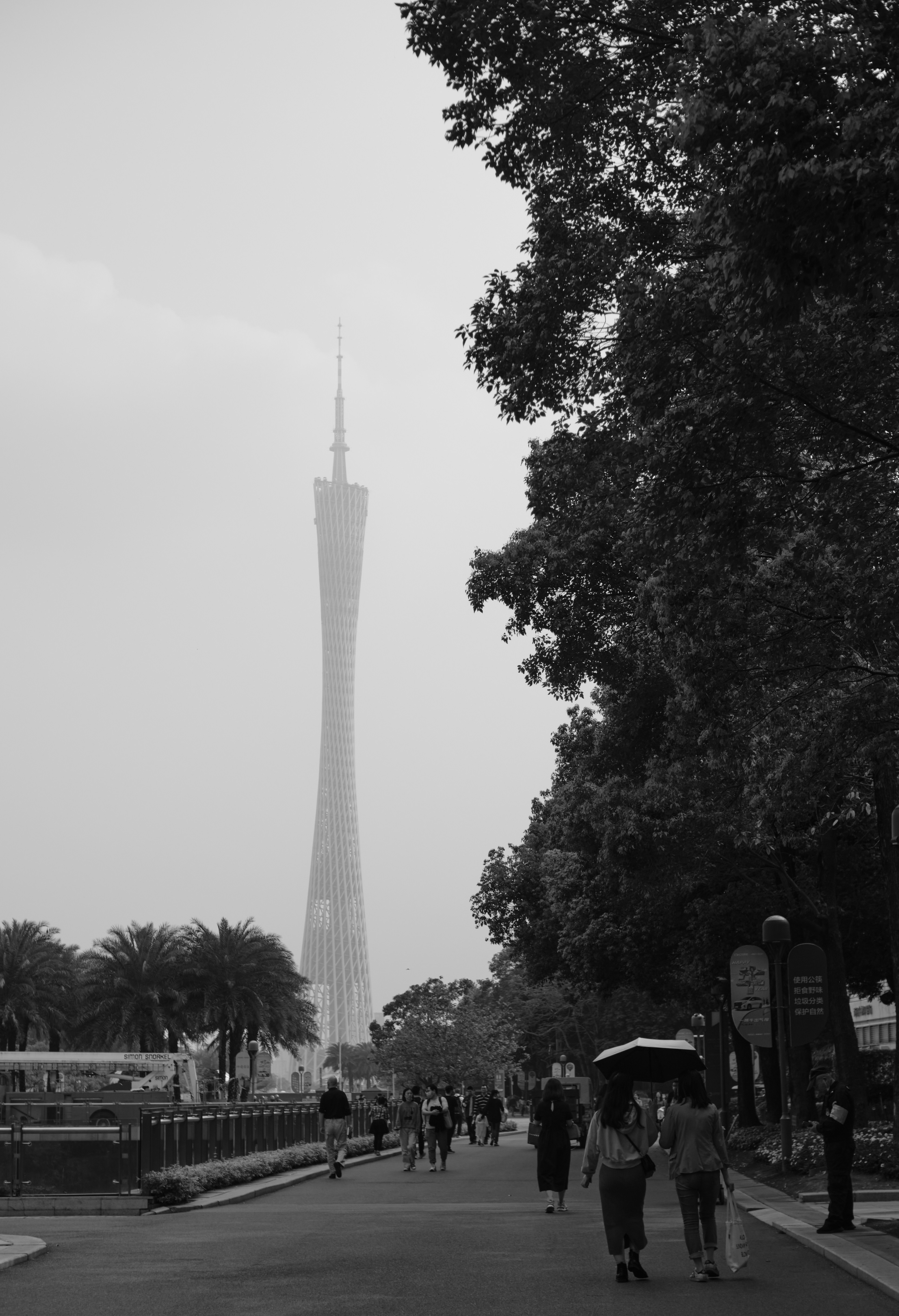 The Guangzhou Tower rises majestically in the background, framed by lush greenery and bustling pedestrians in a serene urban park.