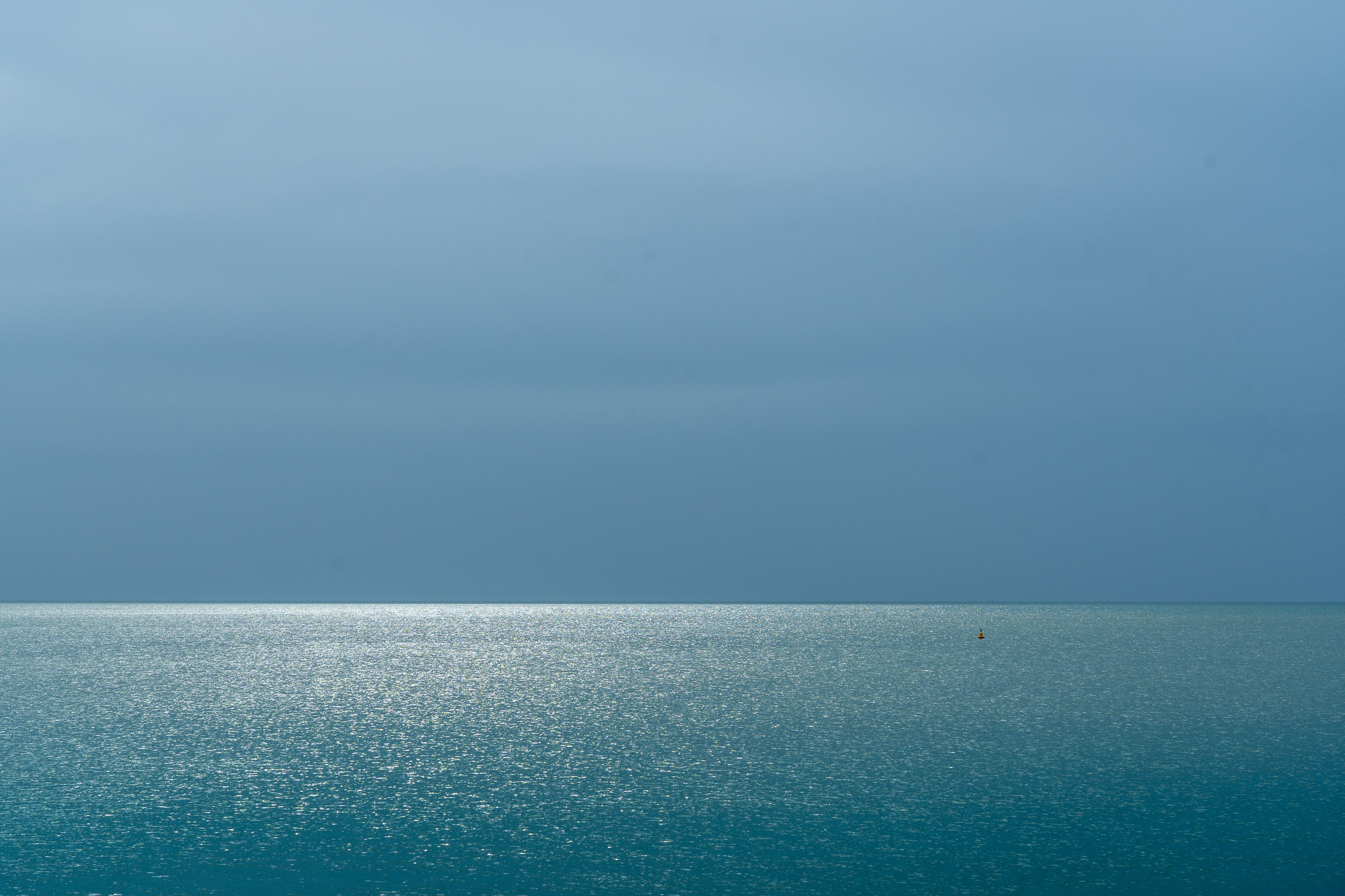 Calm sea reflecting soft light under a cloudy sky, creating a serene atmosphere. The image captures the essence of peaceful solitude.