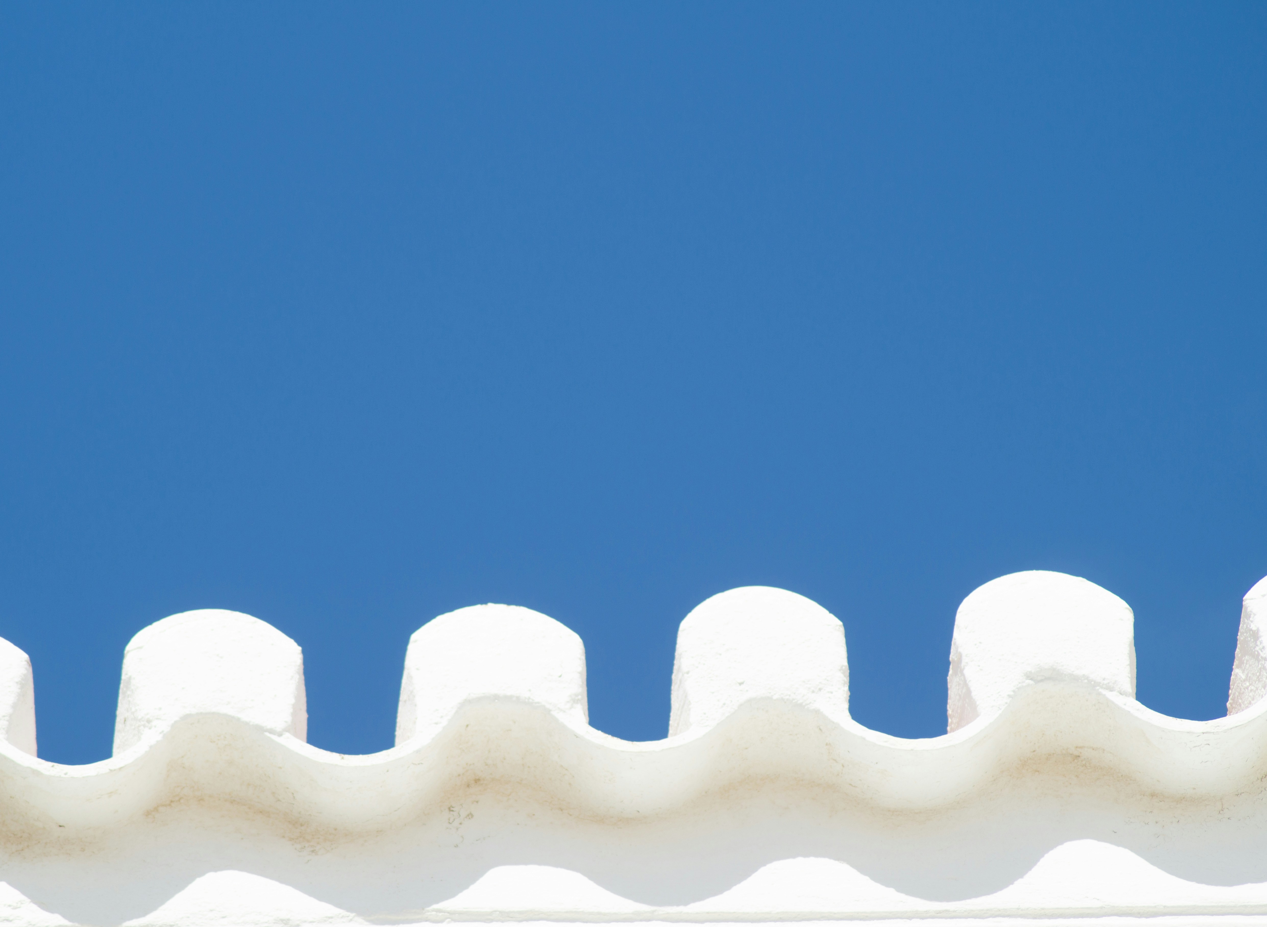 Curved white architectural detail contrasting with a clear blue sky.