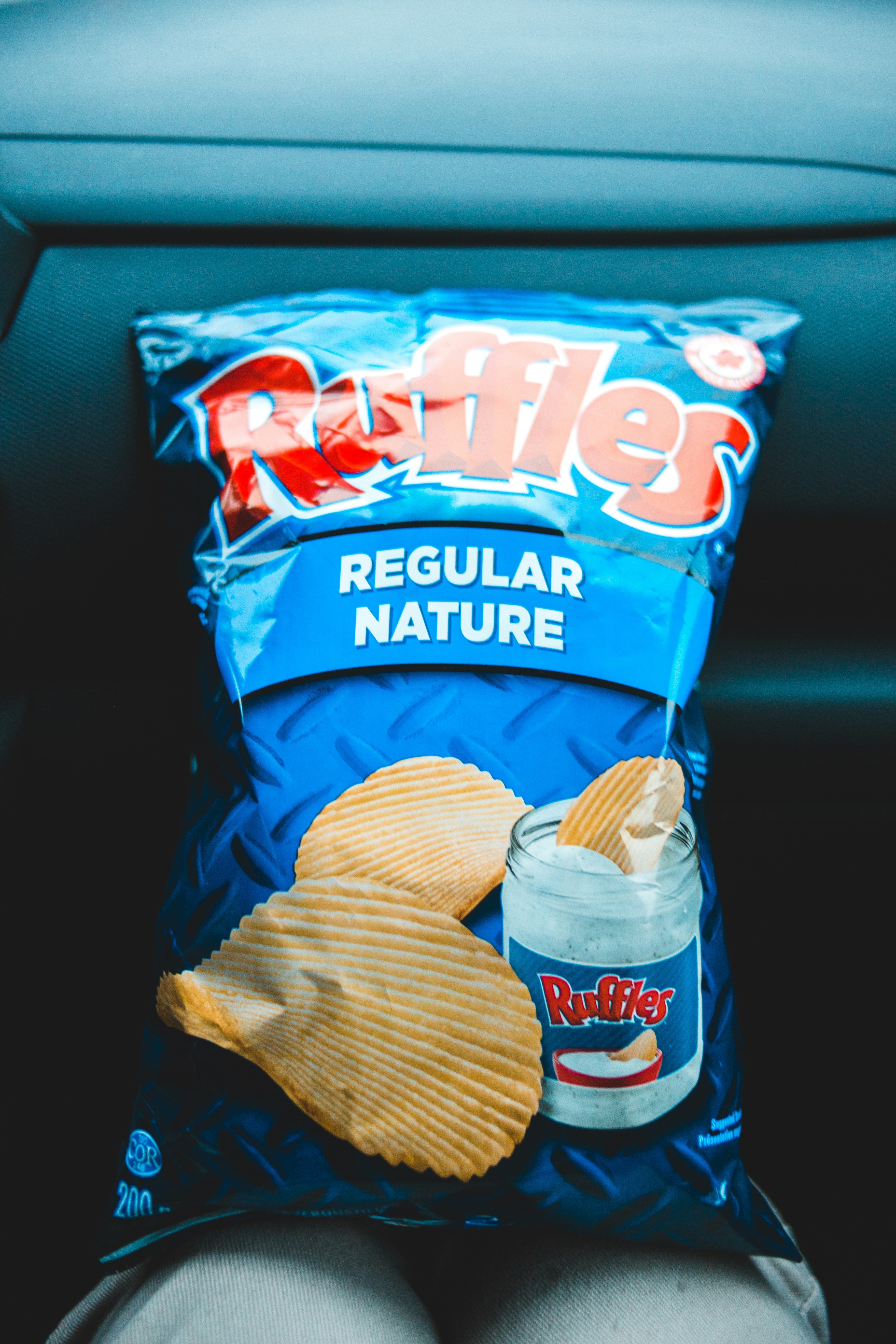 Blue Ruffles on the Dashboard: A Quiet Snack Moment in Transit