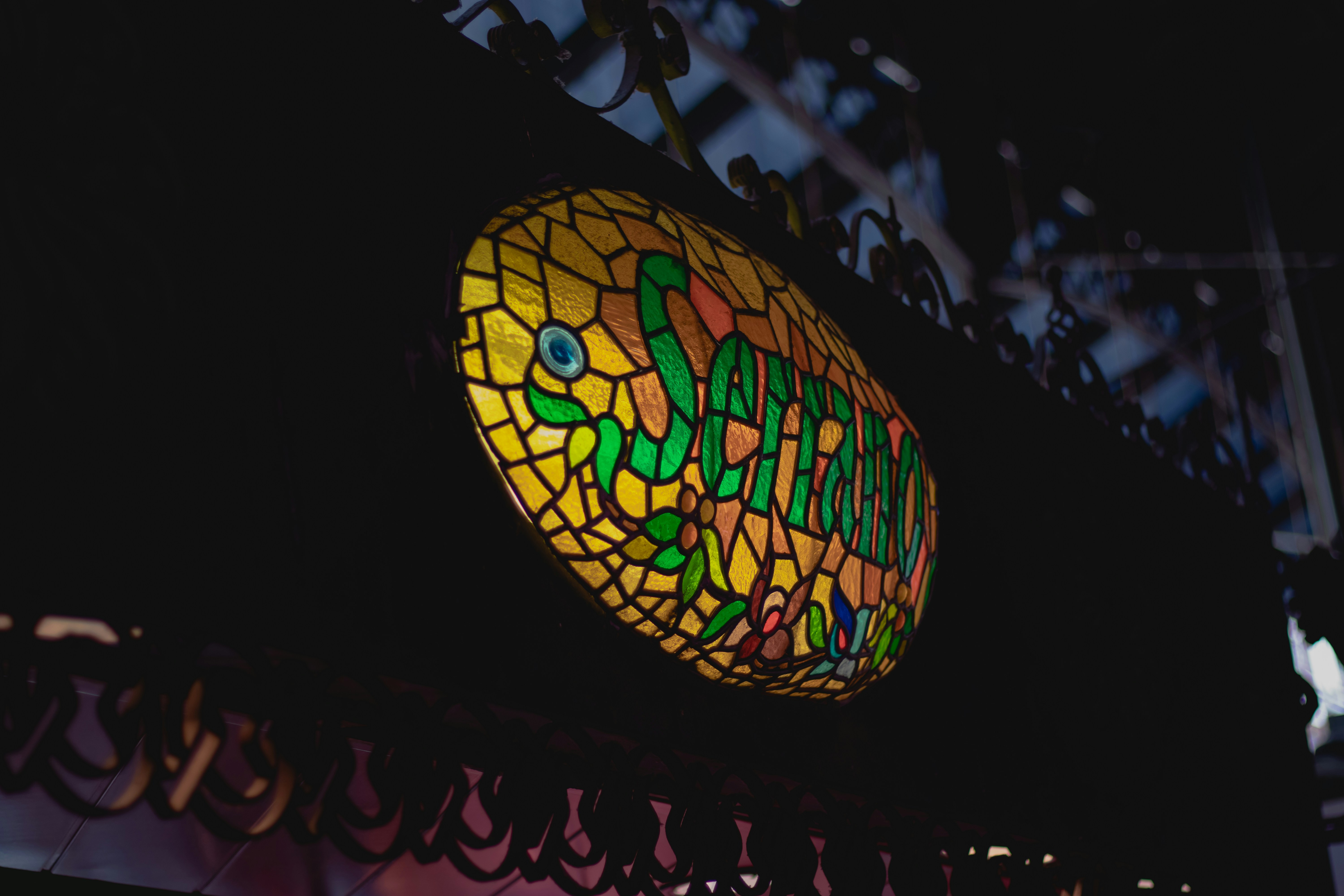 Colorful stained glass sign featuring intricate designs and the name 'Serpentino' illuminated against a dark background.