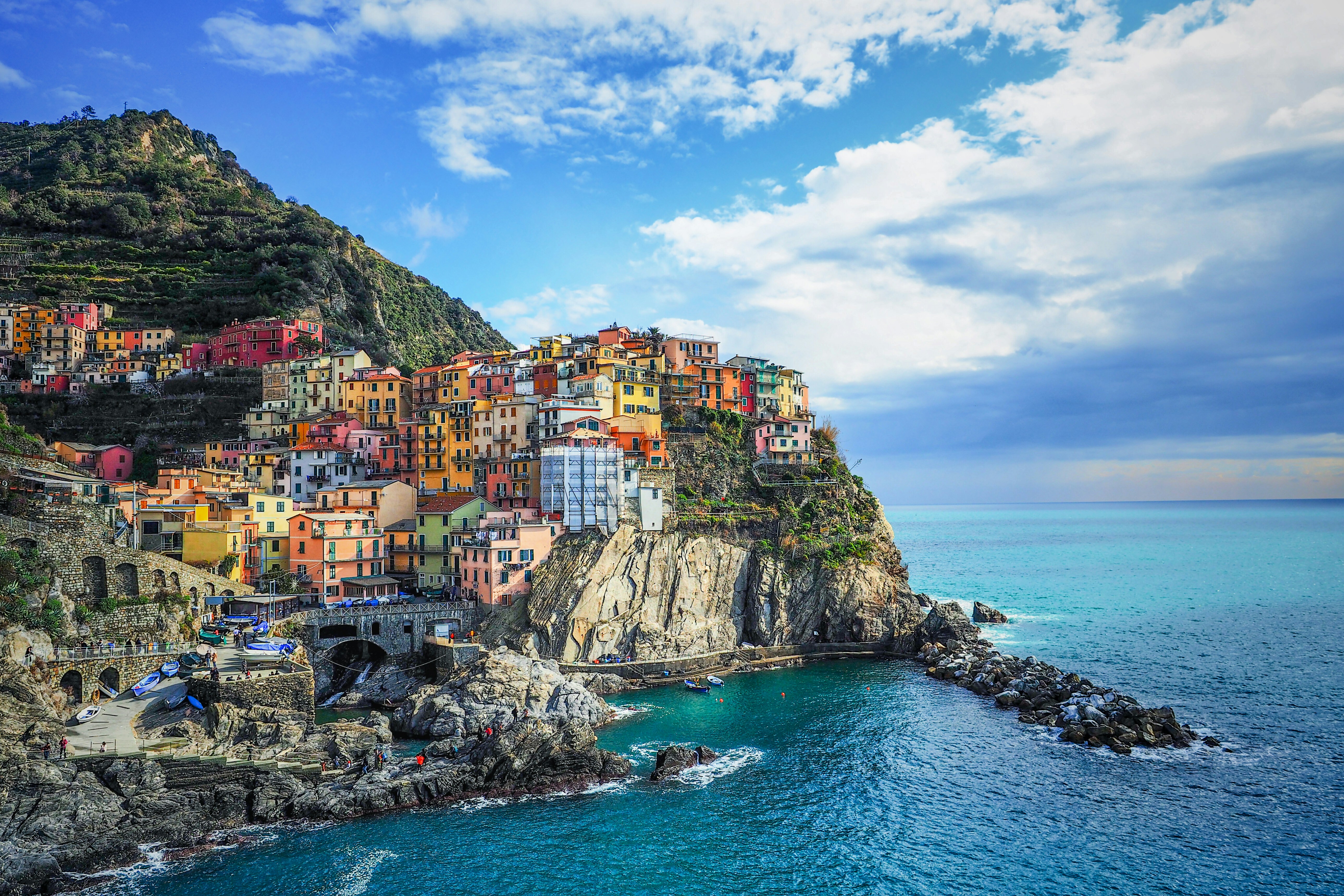 Vibrant coastal village perched on rugged cliffs, showcasing a blend of colorful buildings against a backdrop of azure waters and dramatic skies.