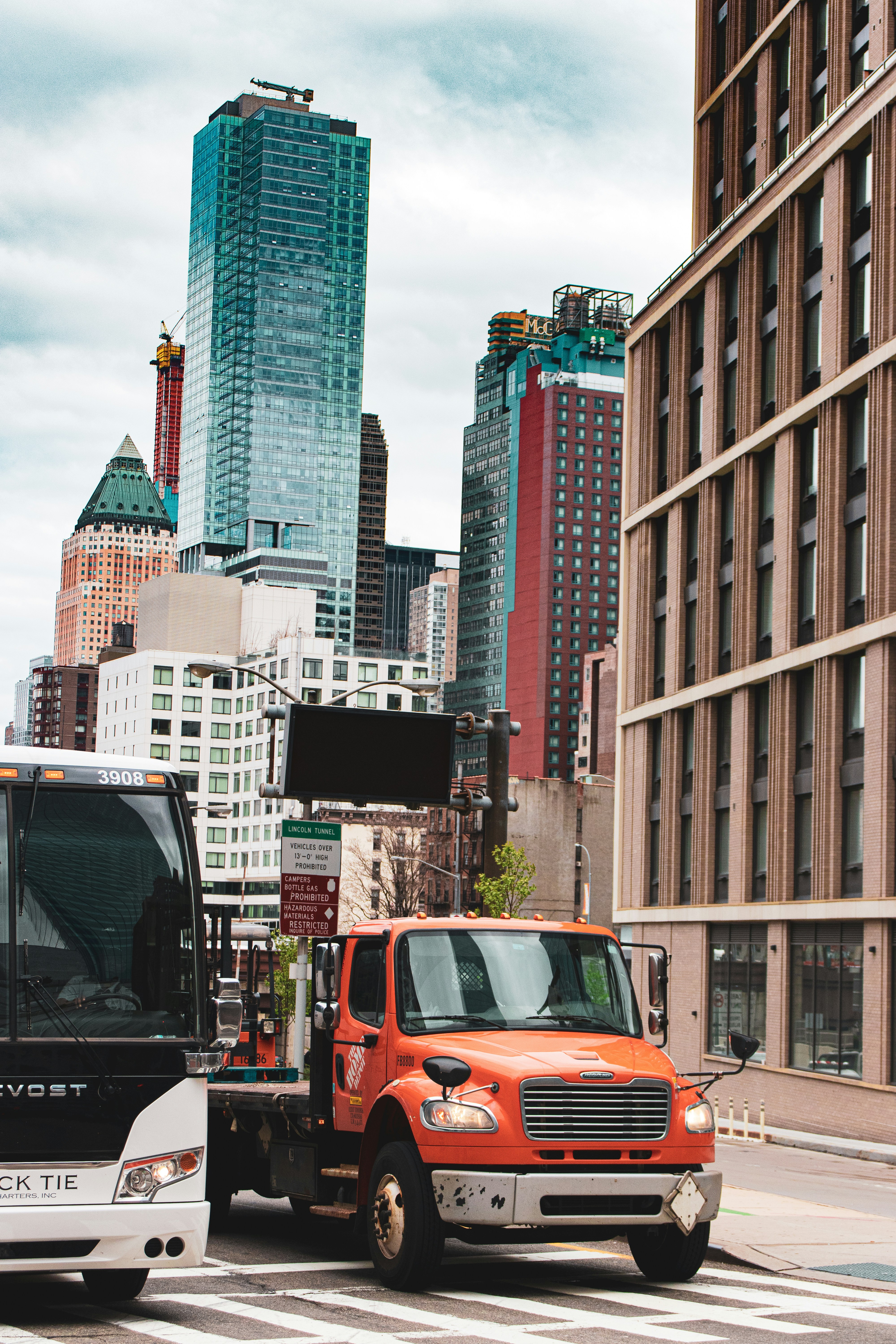 Orange utility truck anchors the street against a canyon of glass and brick