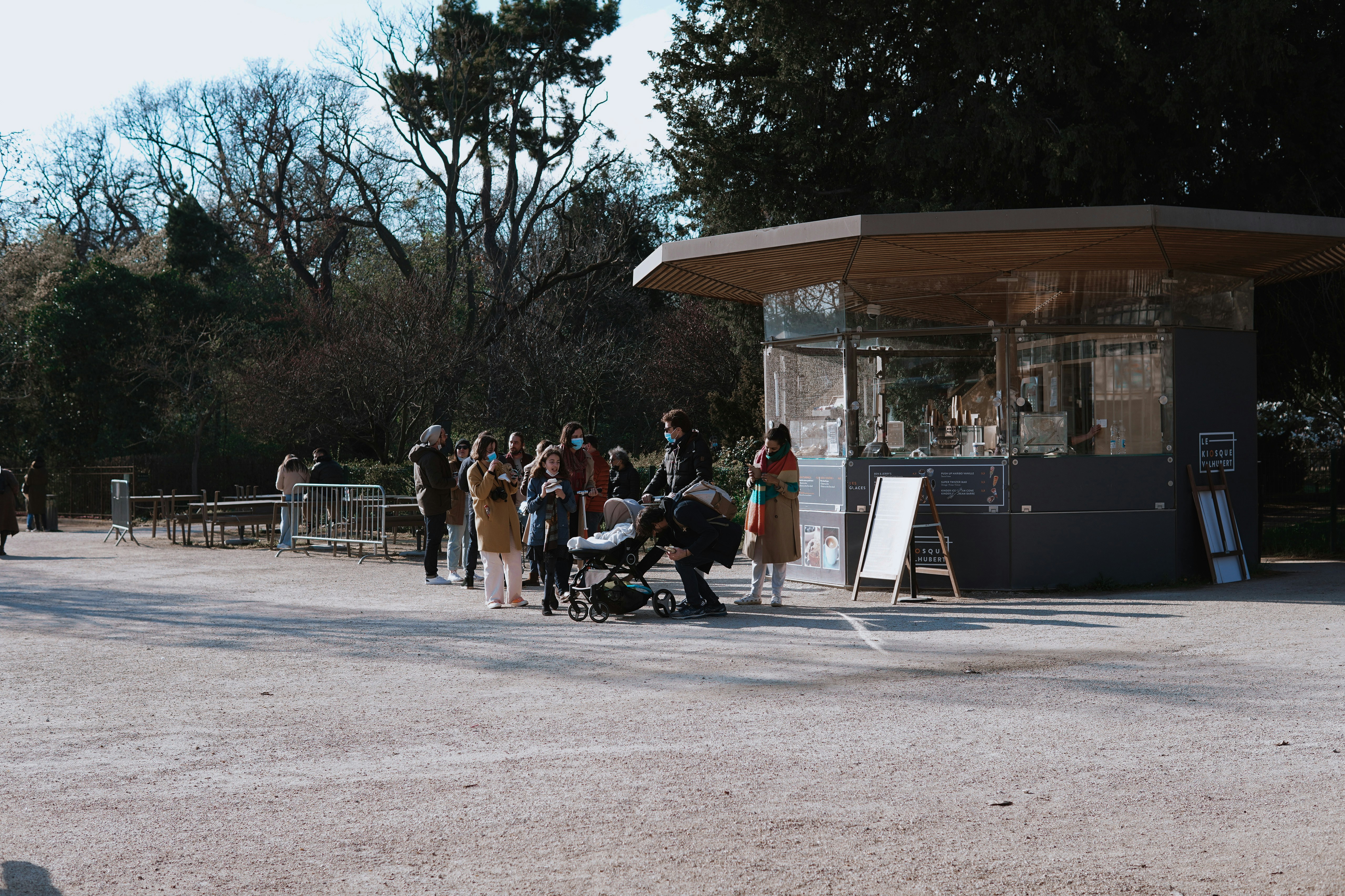 Visitors congregate around a modern kiosk in a serene park setting, showcasing a blend of nature and community interaction.