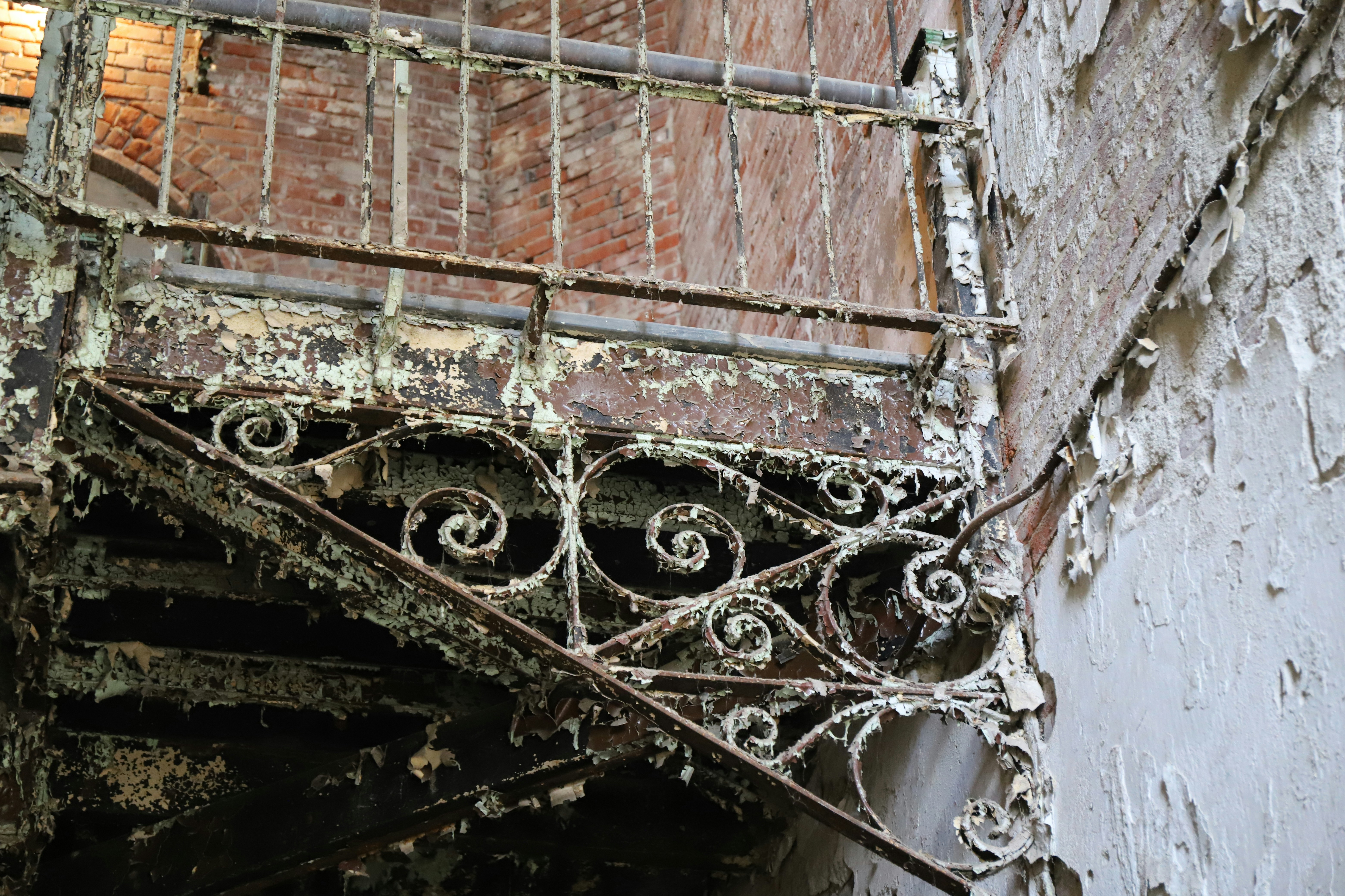Rust and Decay: Ornate Balcony Fragments Clinging to Crumbling Brick