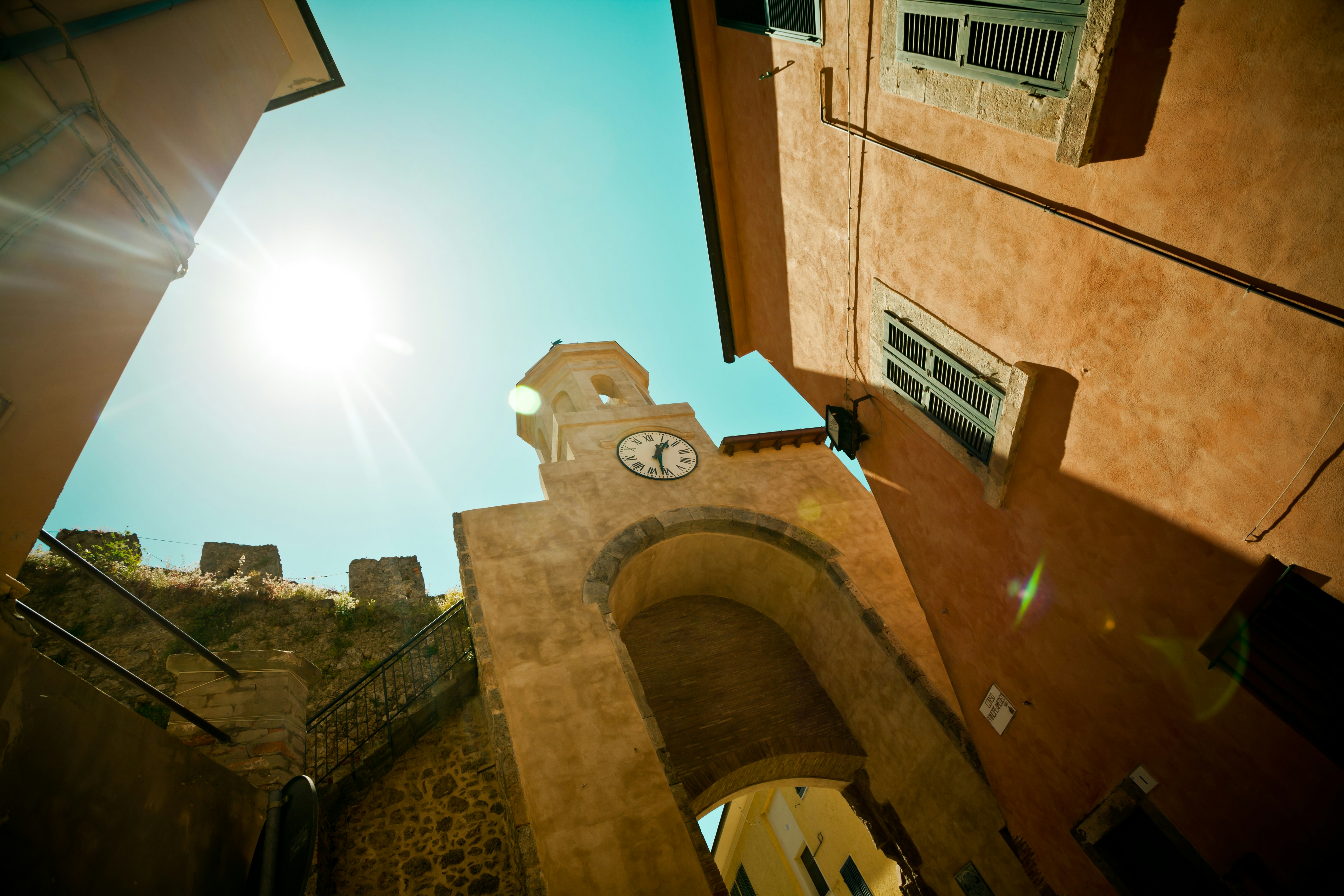 Sunlit Archway Framing a Clock Tower in a Tilted European Alley