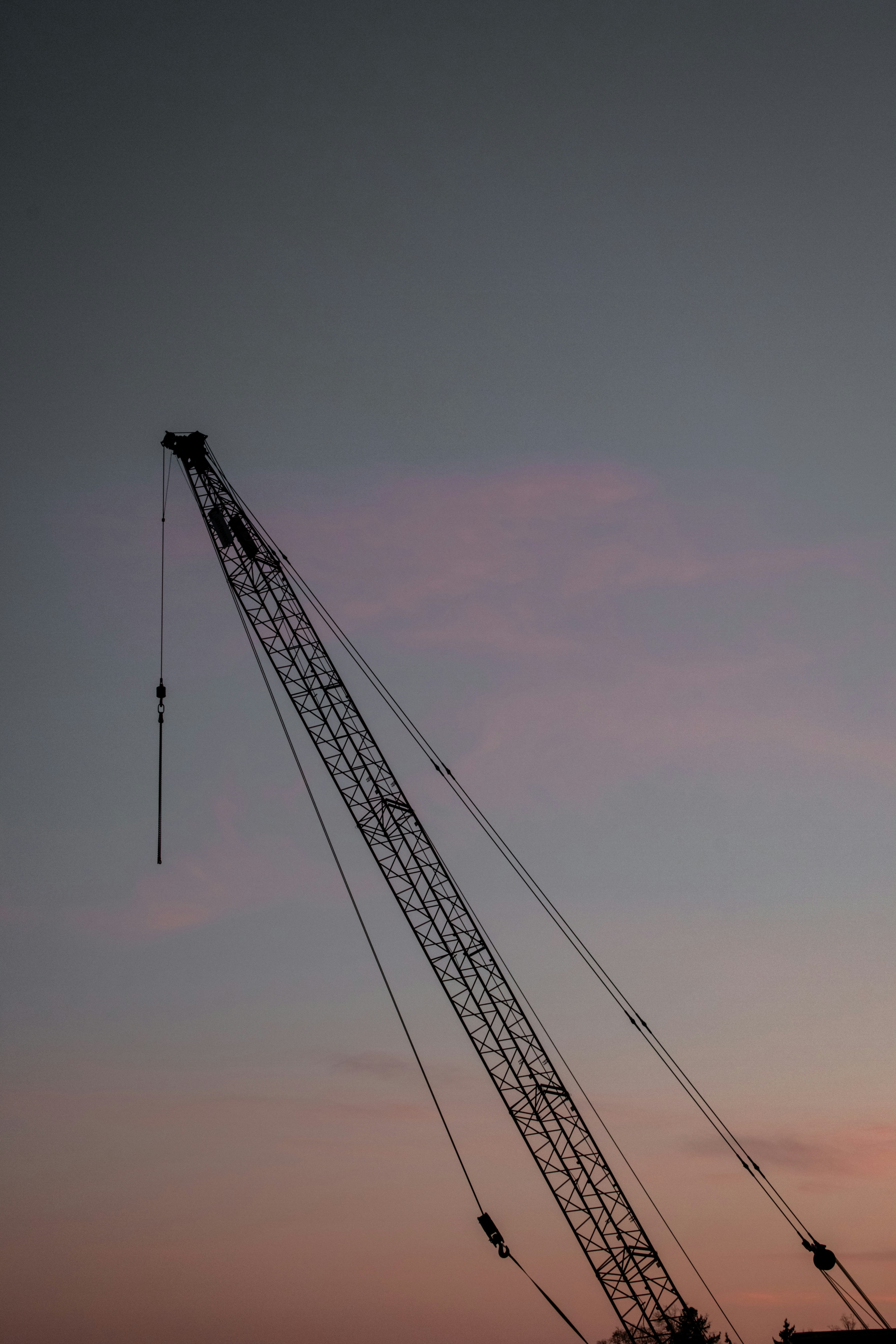 Industrial crane silhouetted against a pastel sky at dusk.