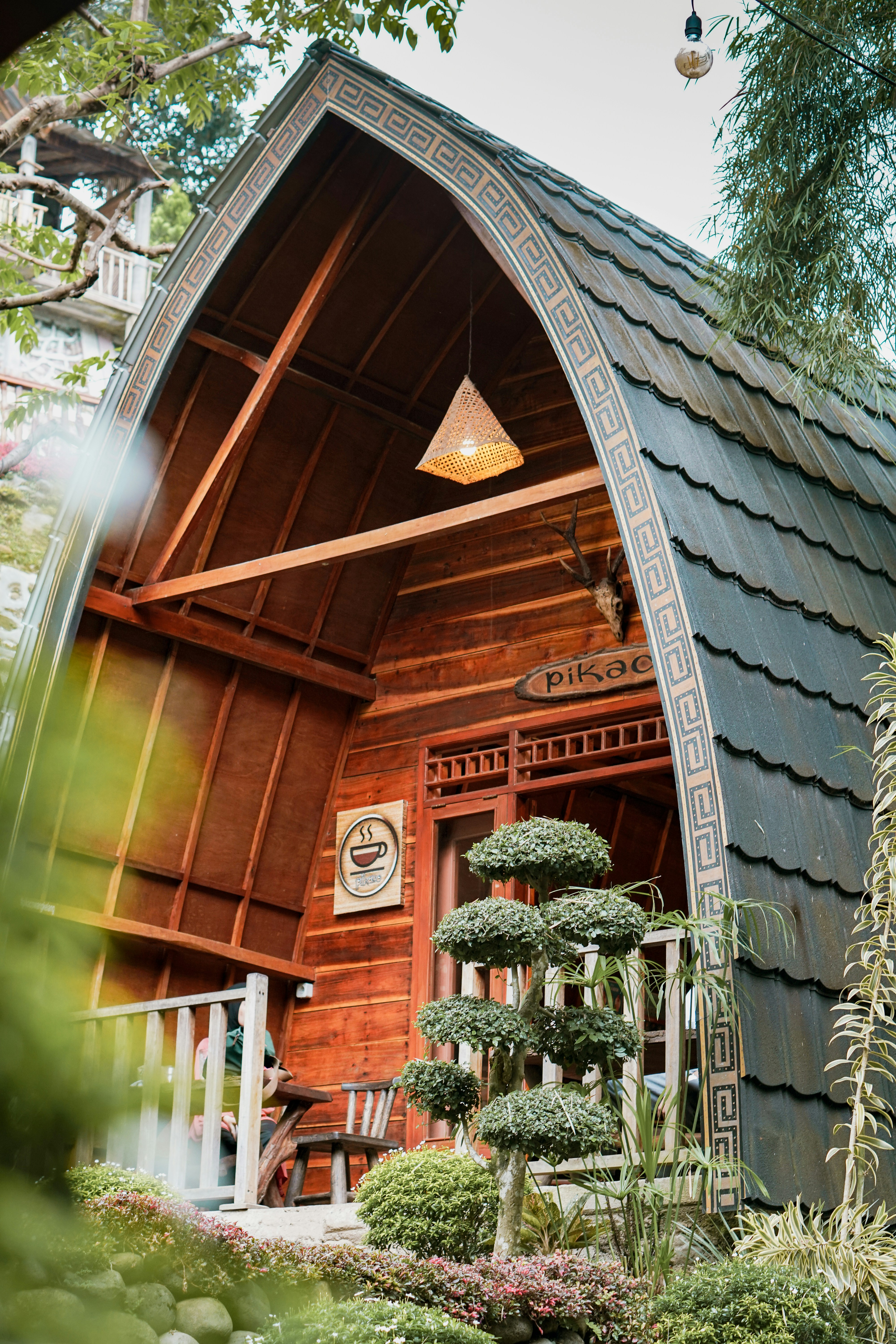 Curved Roof Retreat: A Cozy Wooden Shelter Framed by Verdant Greens