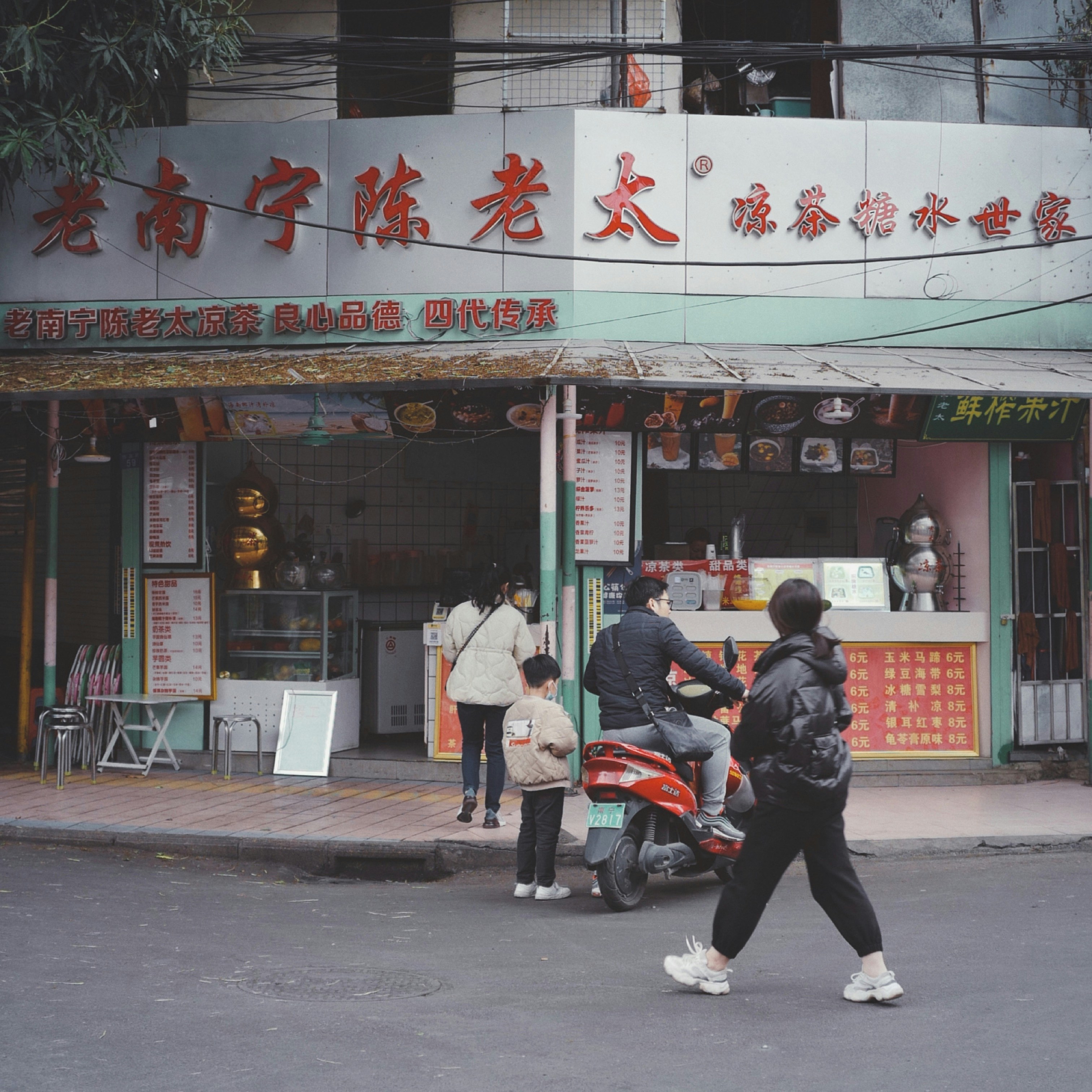 A bustling street scene featuring a food stall with patrons enjoying local cuisine, framed by vibrant signage and urban architecture.