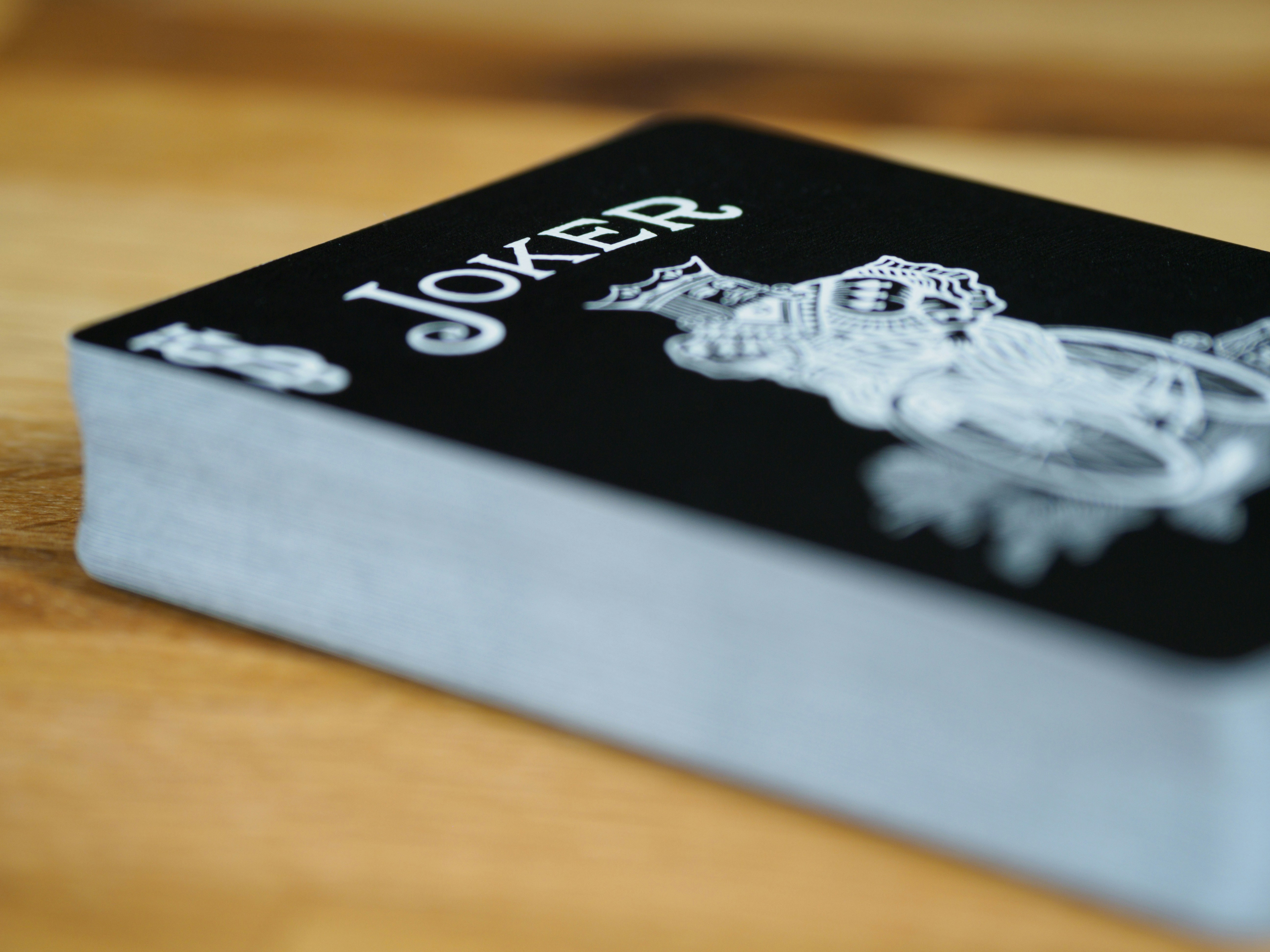 Black Deck of Joker Cards Resting on Wooden Surface
