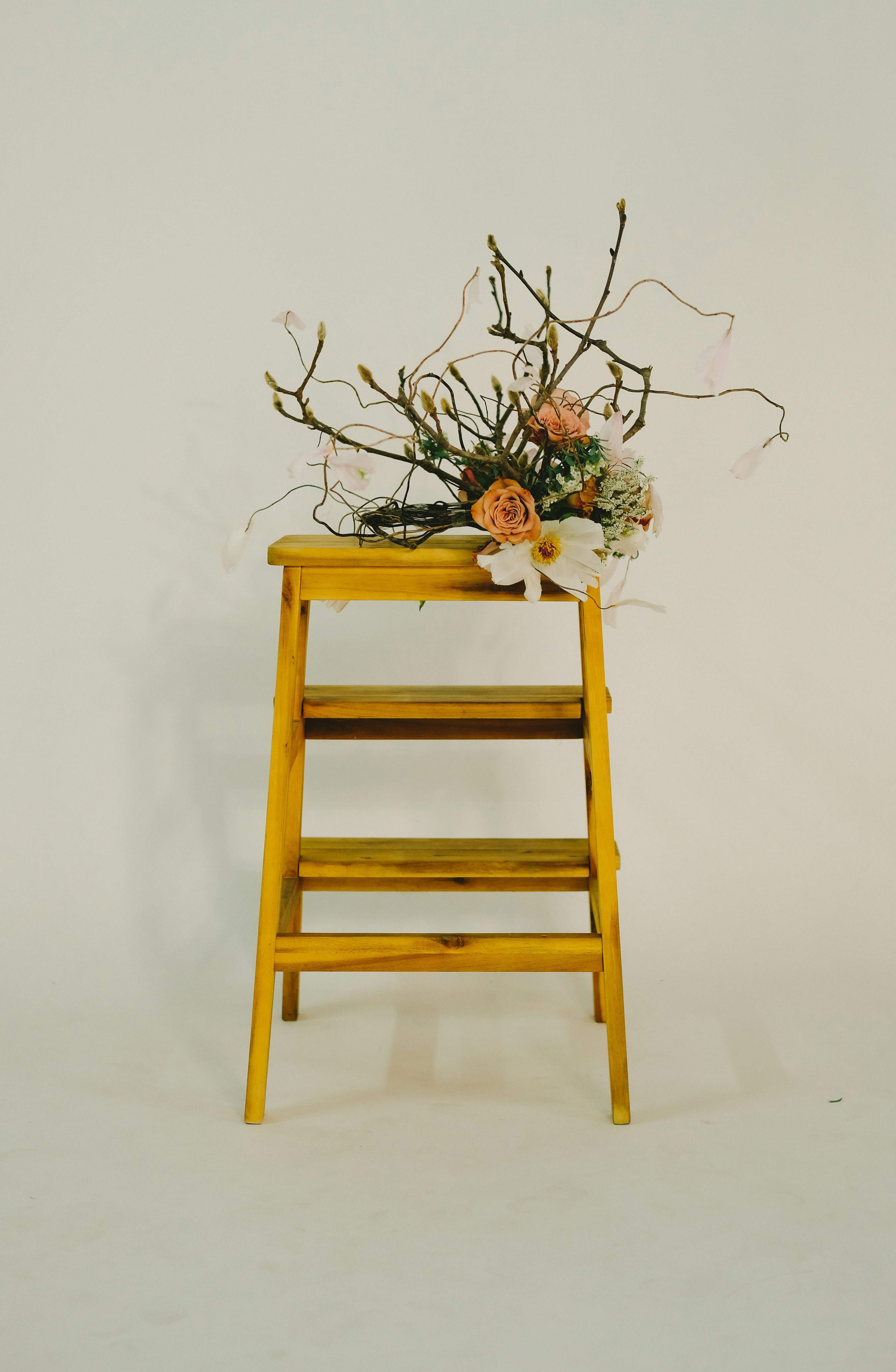Floral Crown on a Simple Wooden Stepladder Against a Pale Studio Backdrop