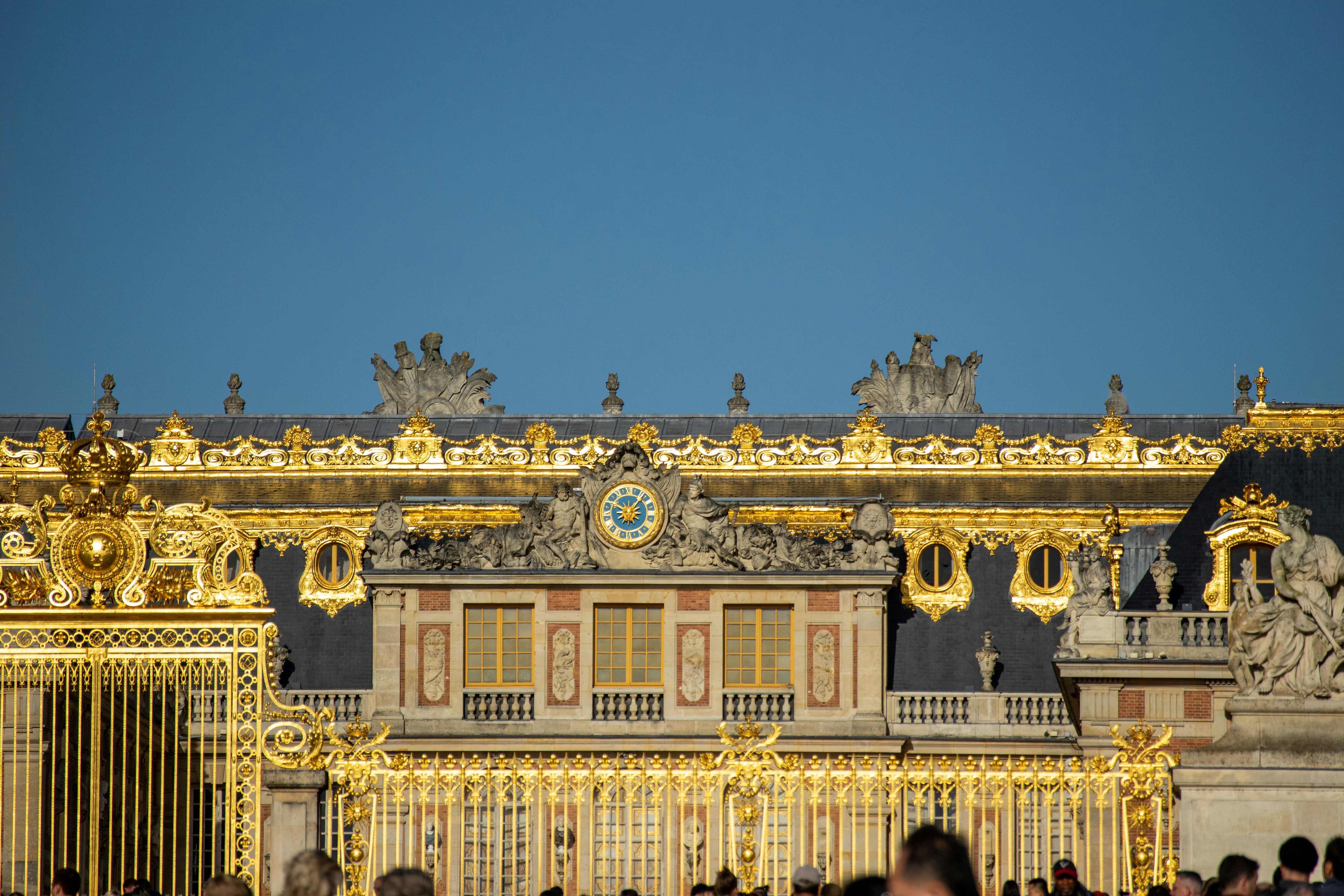 Cobalt Sky over a Gold-Leaf Gate: Intricate Sculptures Guarding a Regal Facade