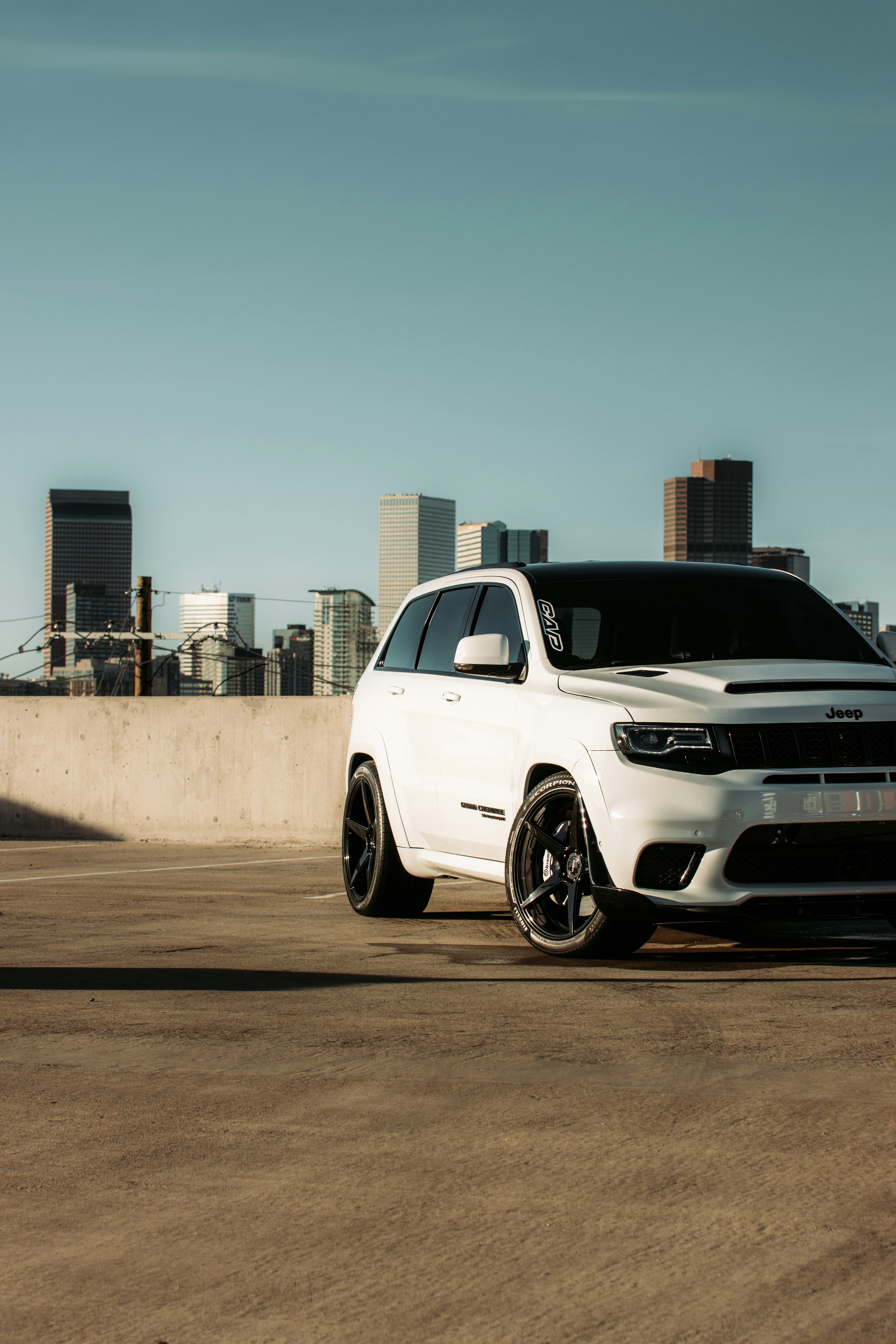 White Jeep Grand Cherokee SRT perched on a rooftop with city skyline