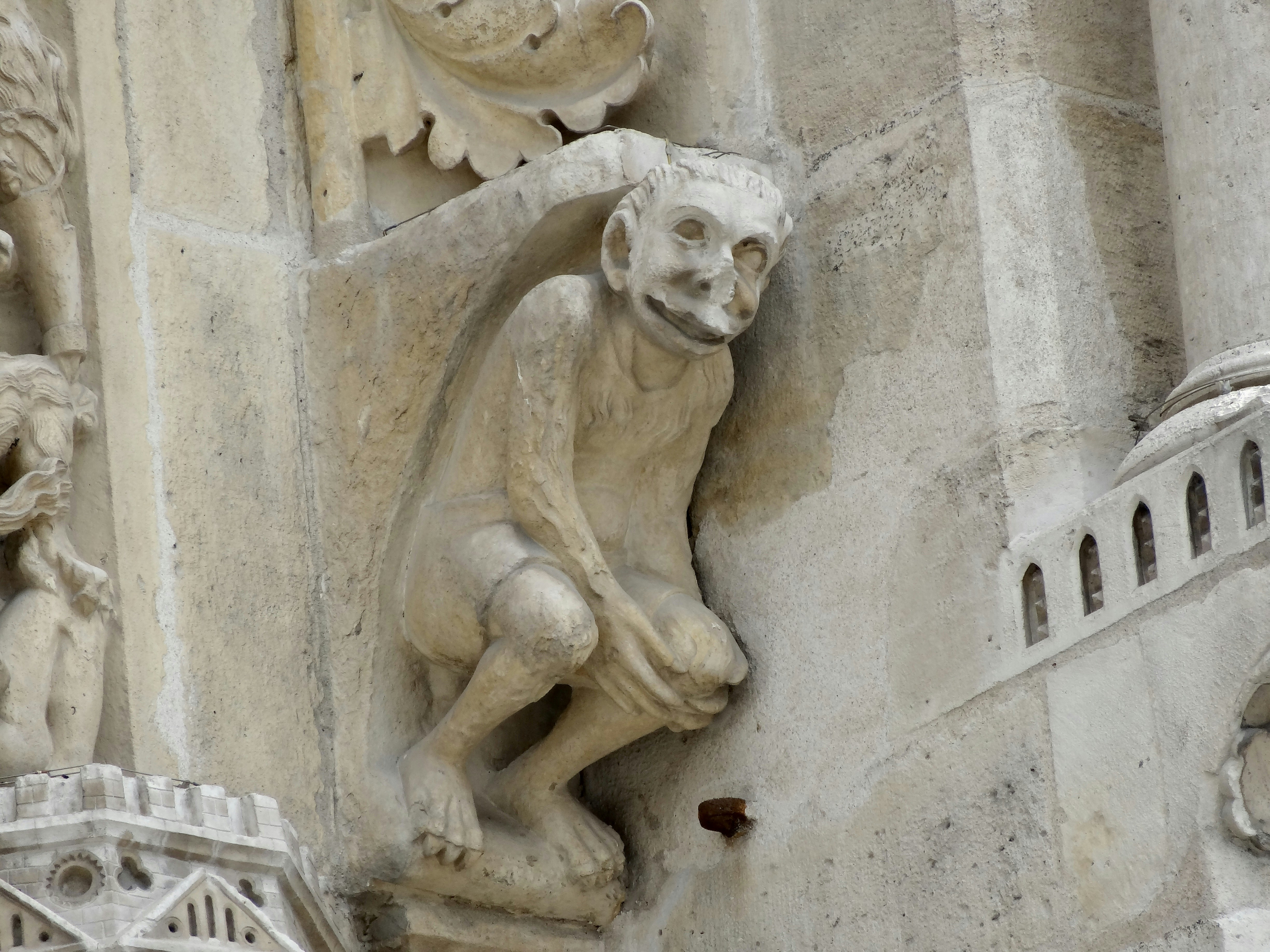 Intricate stone gargoyle perched on a cathedral wall, showcasing detailed craftsmanship and a playful expression.