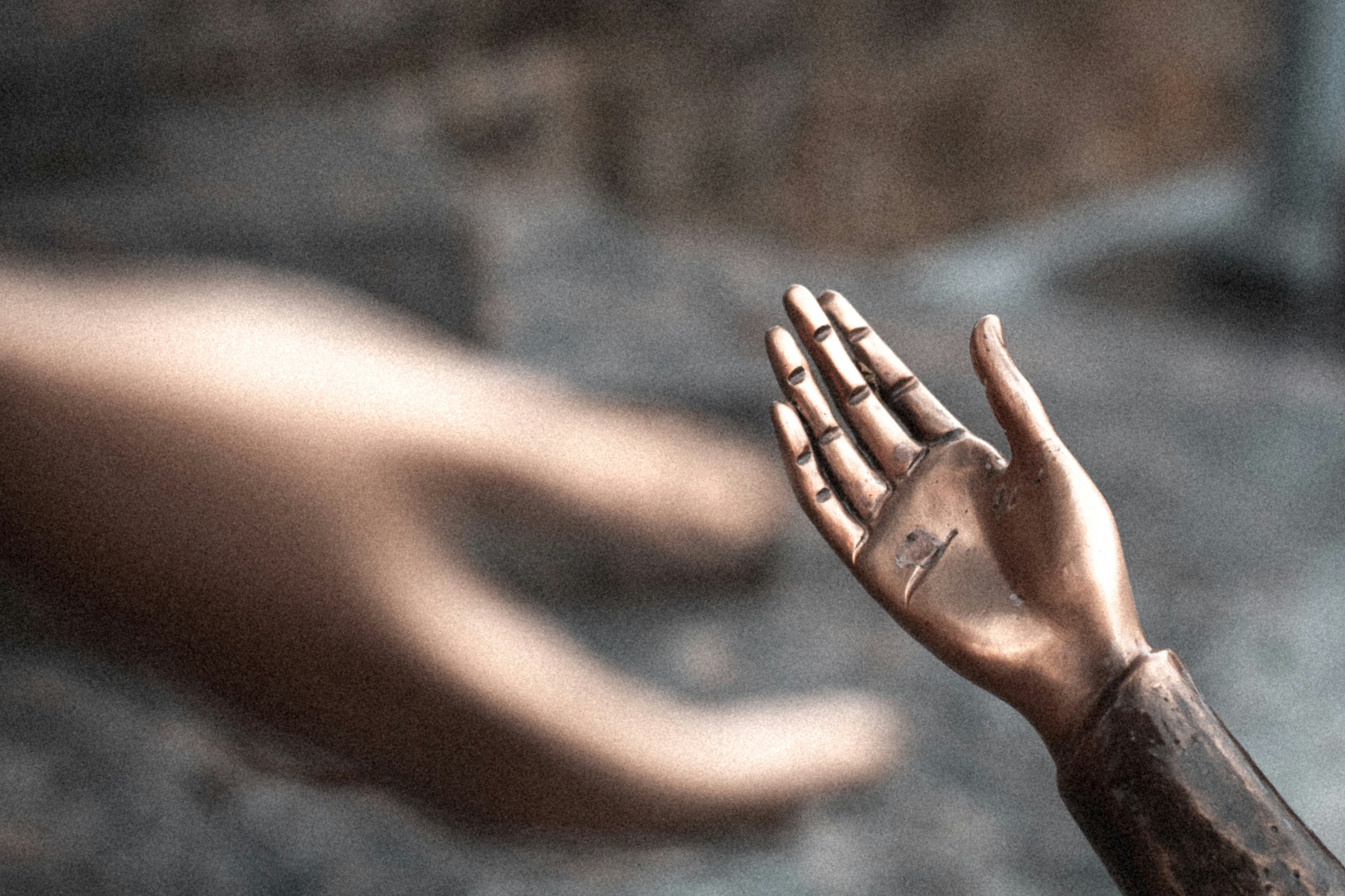 Bronze hands close up originating from two statues opening their arms. 

Shot on Canon EOS 1300D w/ 50mm f1.8
