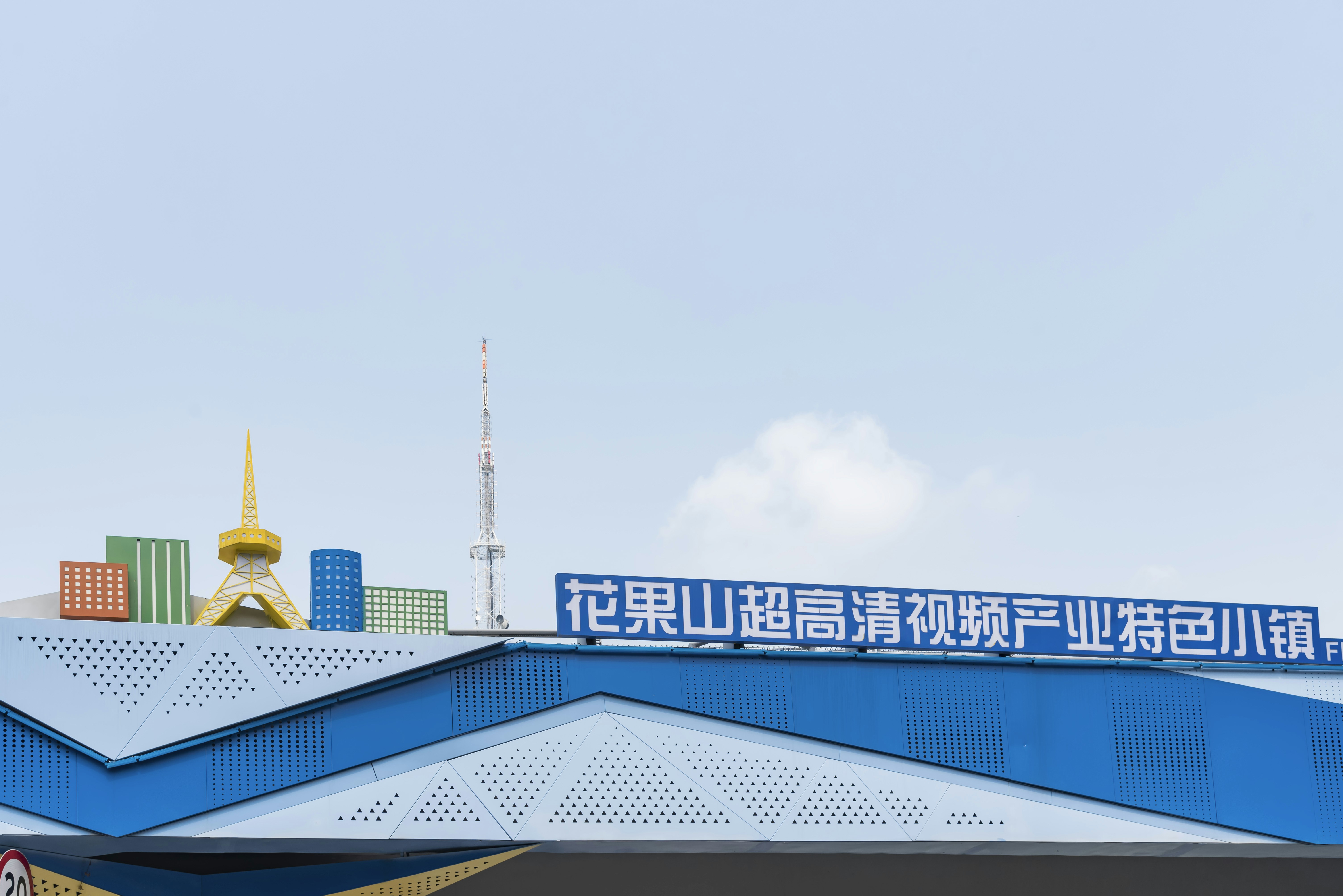 Blue and gray geometric rooftop with a sign against a bright sky.