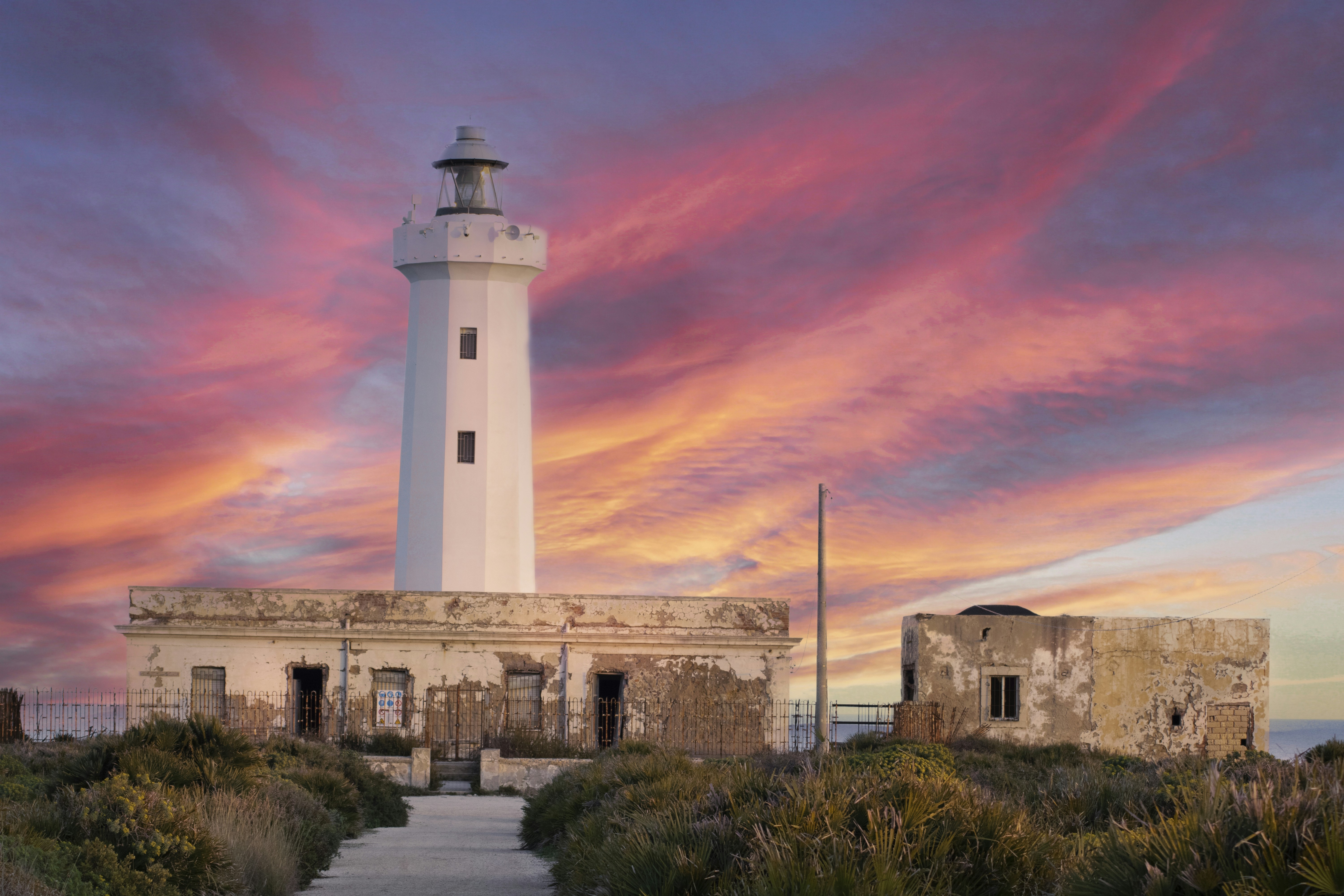 White concrete lighthouse near brown concrete building during daytime ...