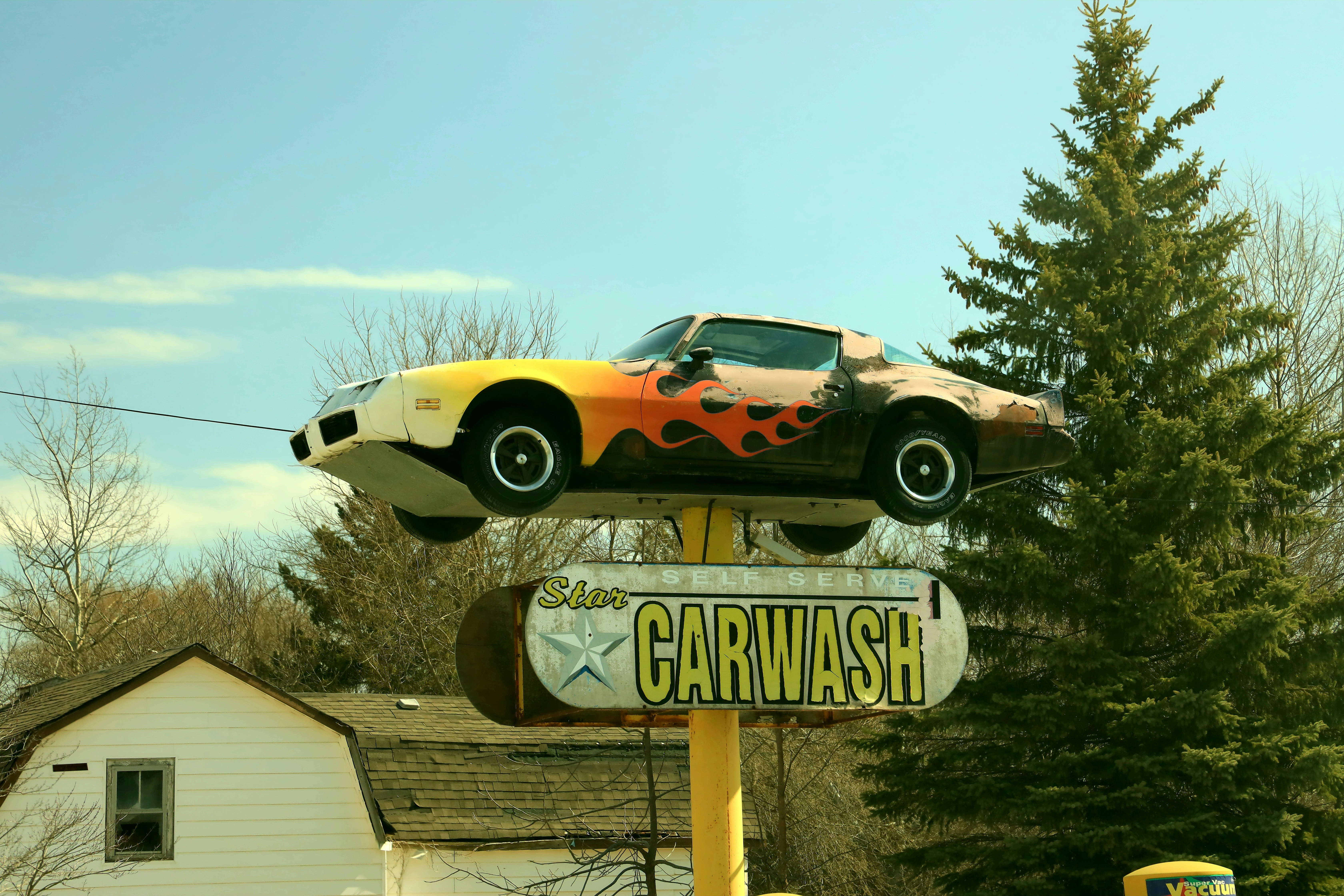 Flame-Painted Muscle Car Perched Over a Retro Carwash Sign