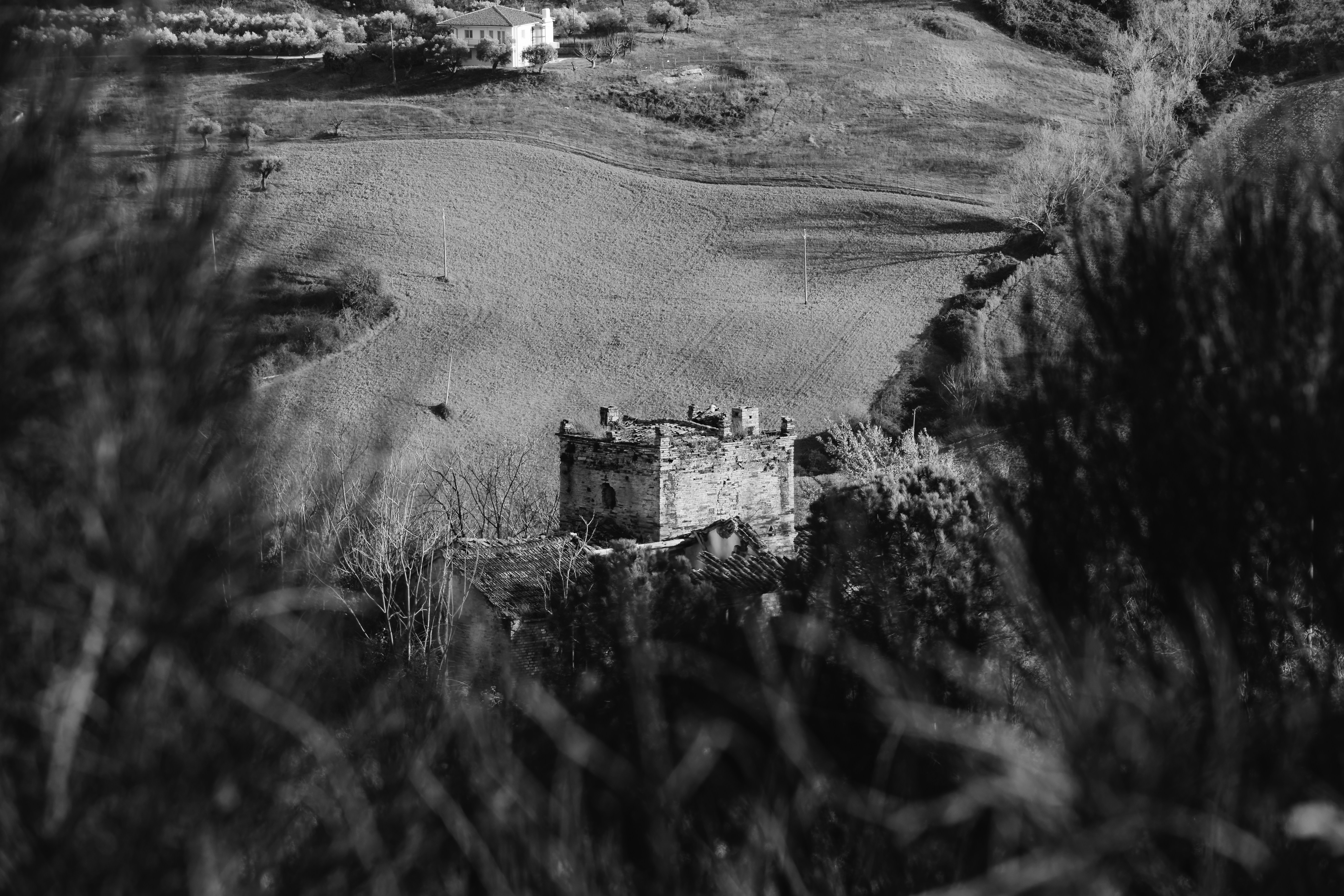 A weathered stone tower stands amidst rolling hills, framed by sparse vegetation, evoking a sense of history and solitude.