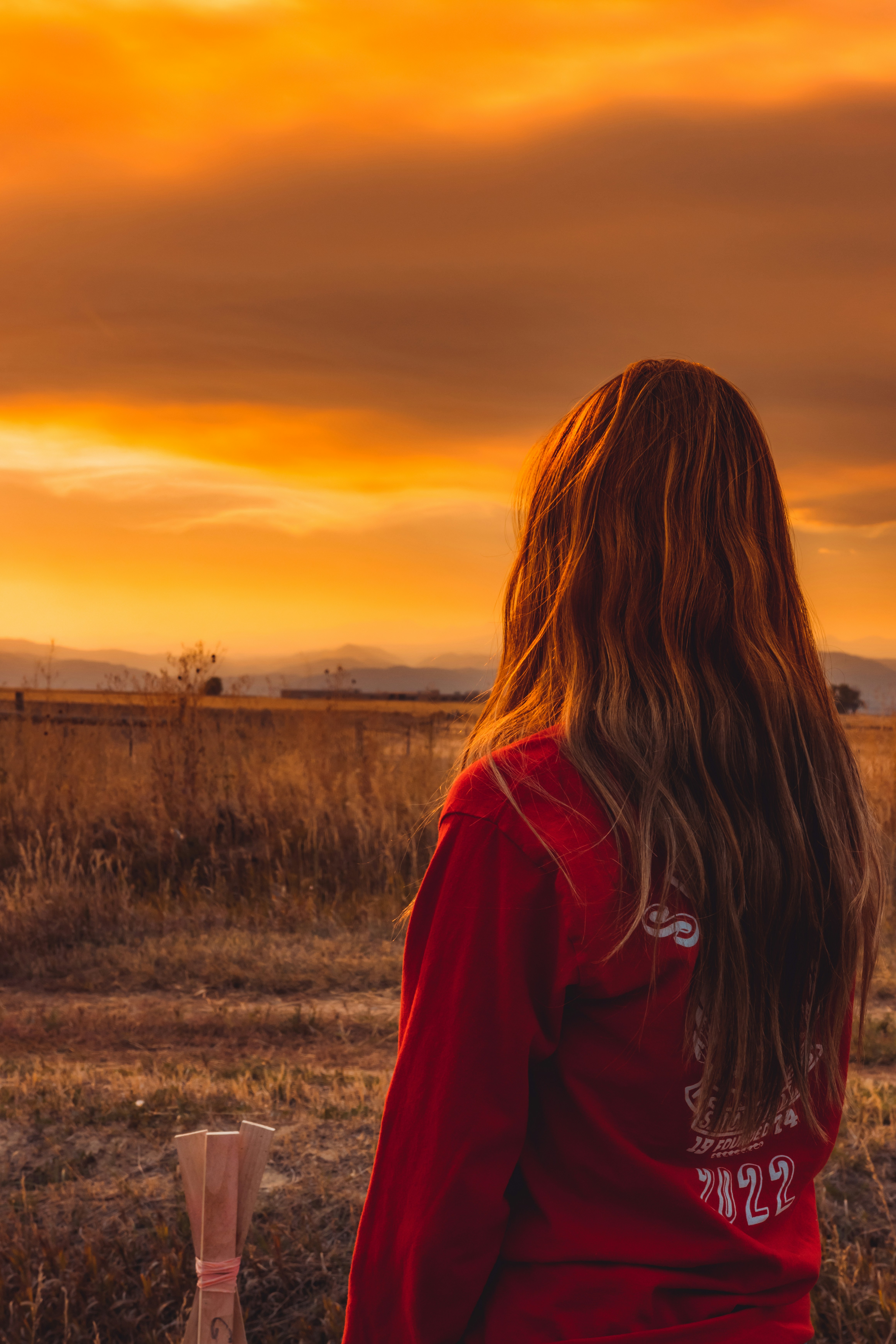 Desert Sunset Portrait: A Red-Hooded Figure Against Olive Plains