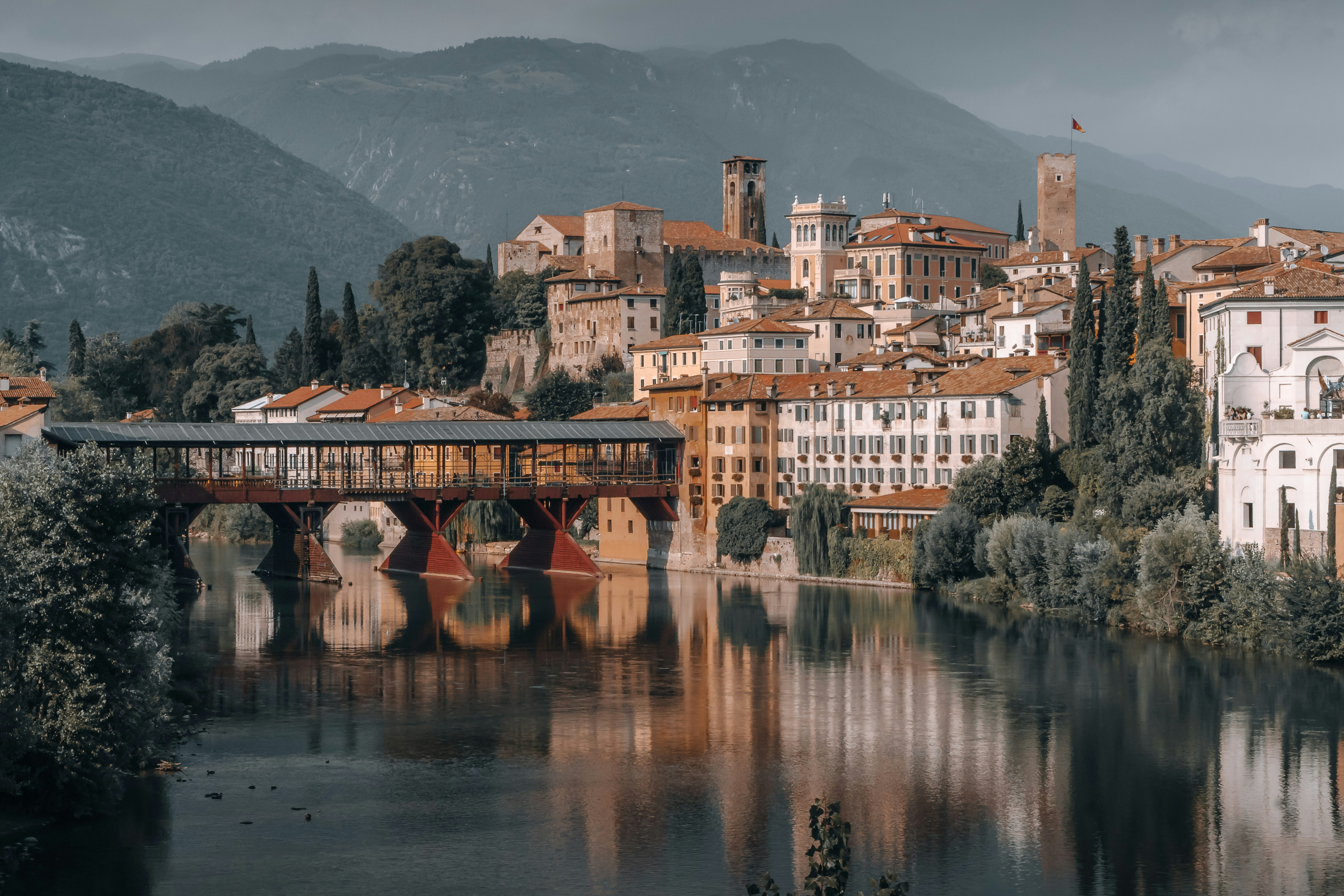 Rustic bridge and quaint townscape reflected in a calm river with misty mountains in the background.