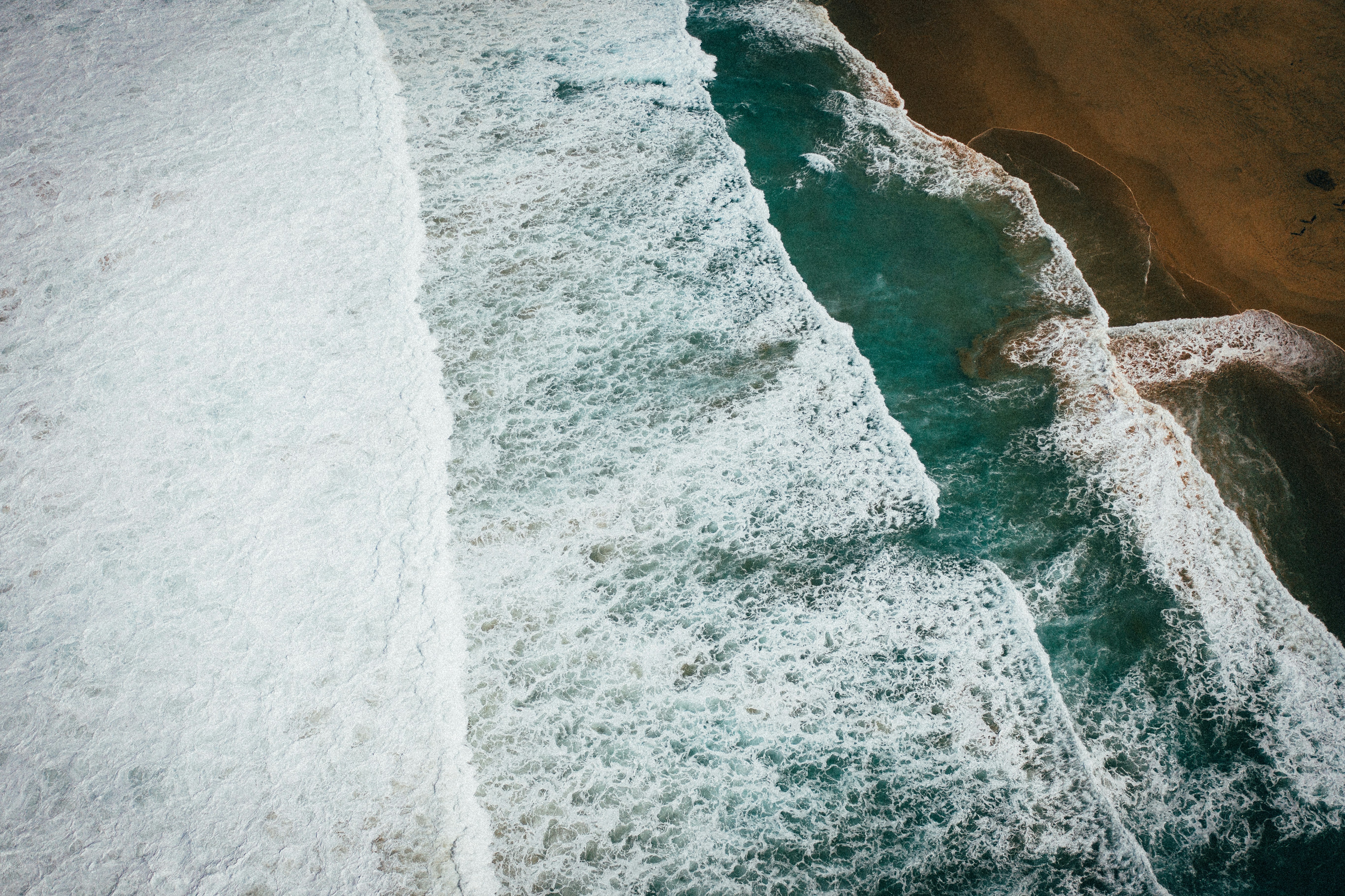Dynamic waves crashing onto a sandy beach, showcasing the interplay of water and land. The scene captures the natural rhythm of the ocean.