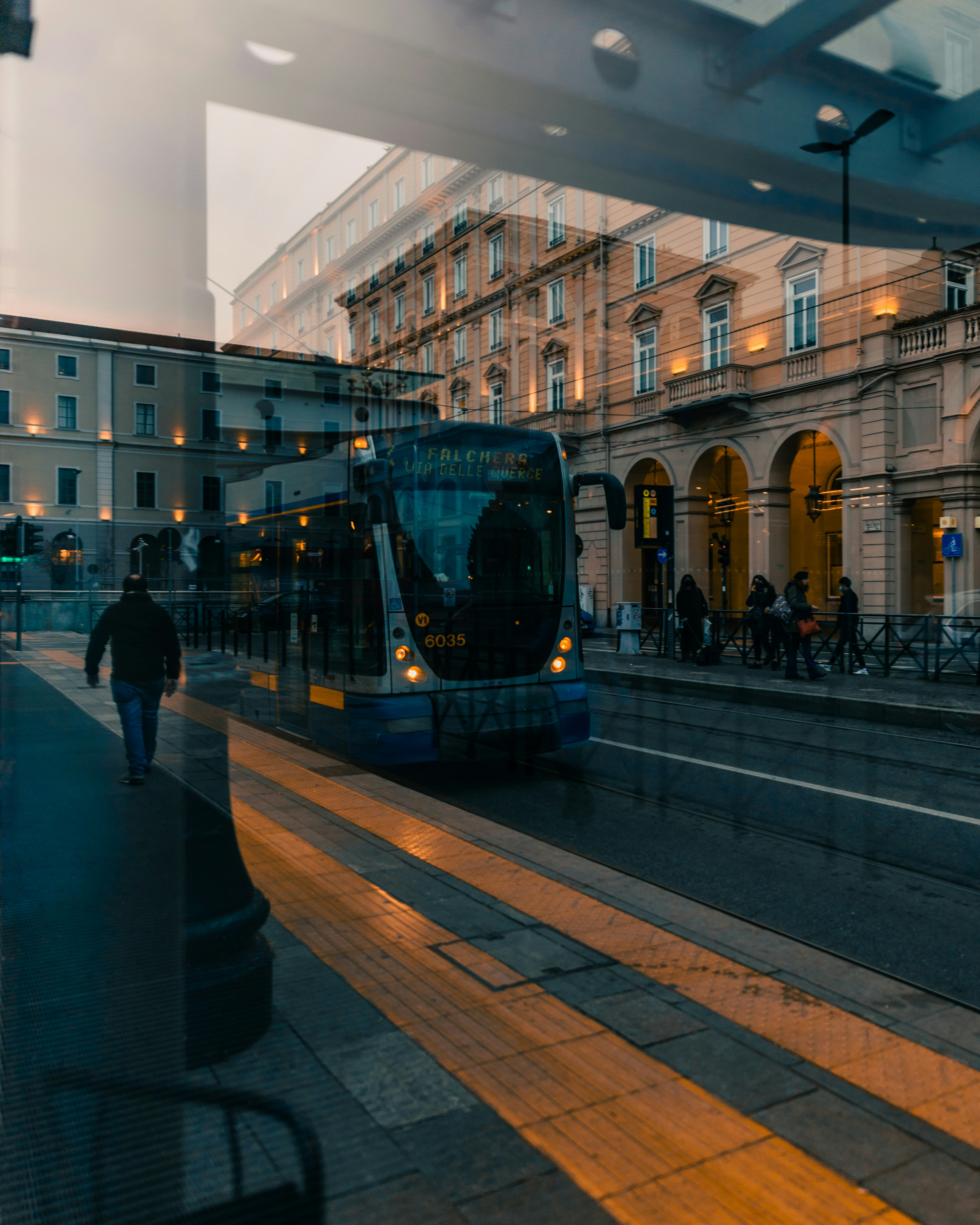 City bus navigating through a bustling street, reflected in a glass surface, capturing the essence of urban mobility.