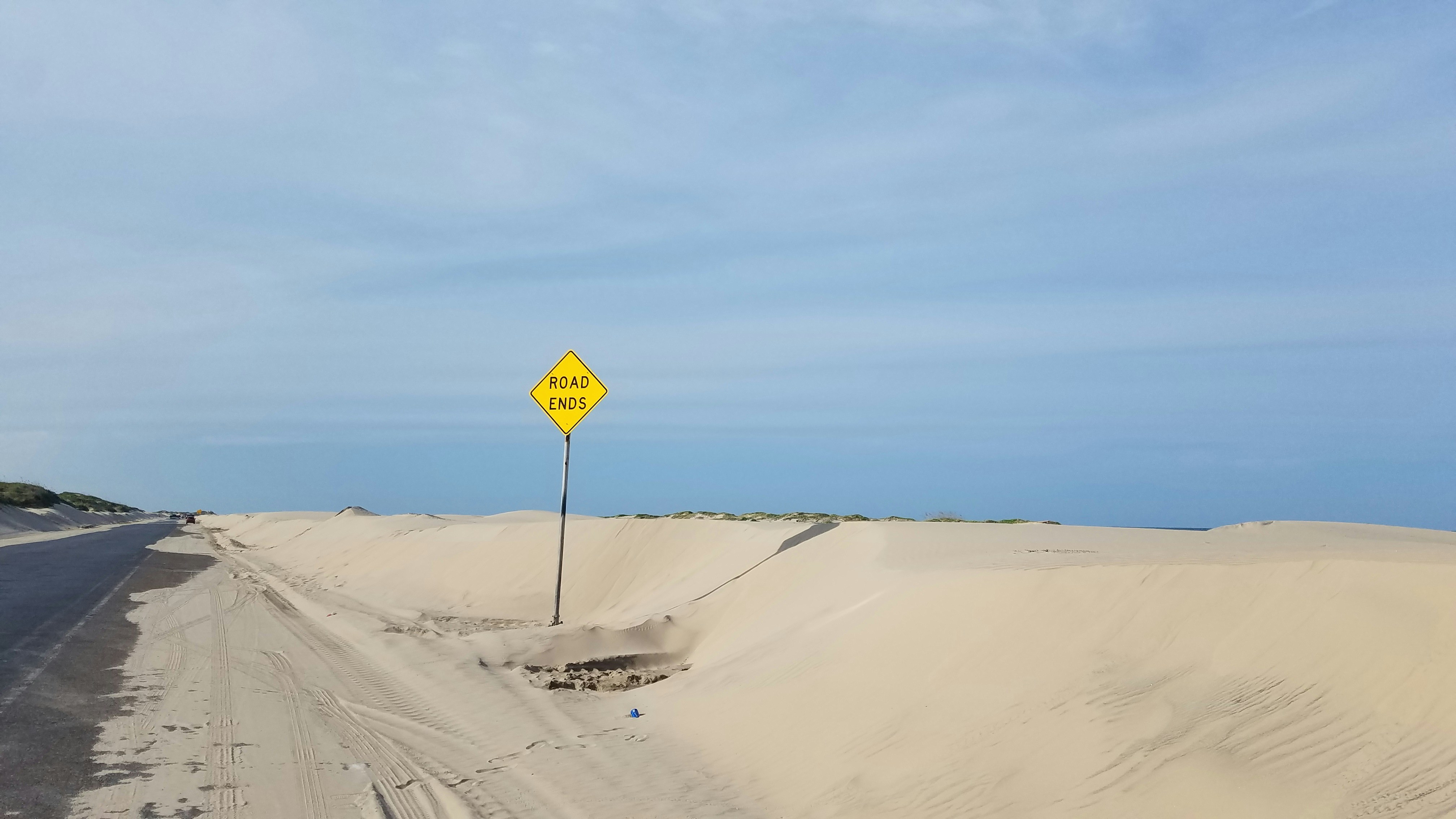 Yellow and black road sign on white sand photo – Free South padre ...