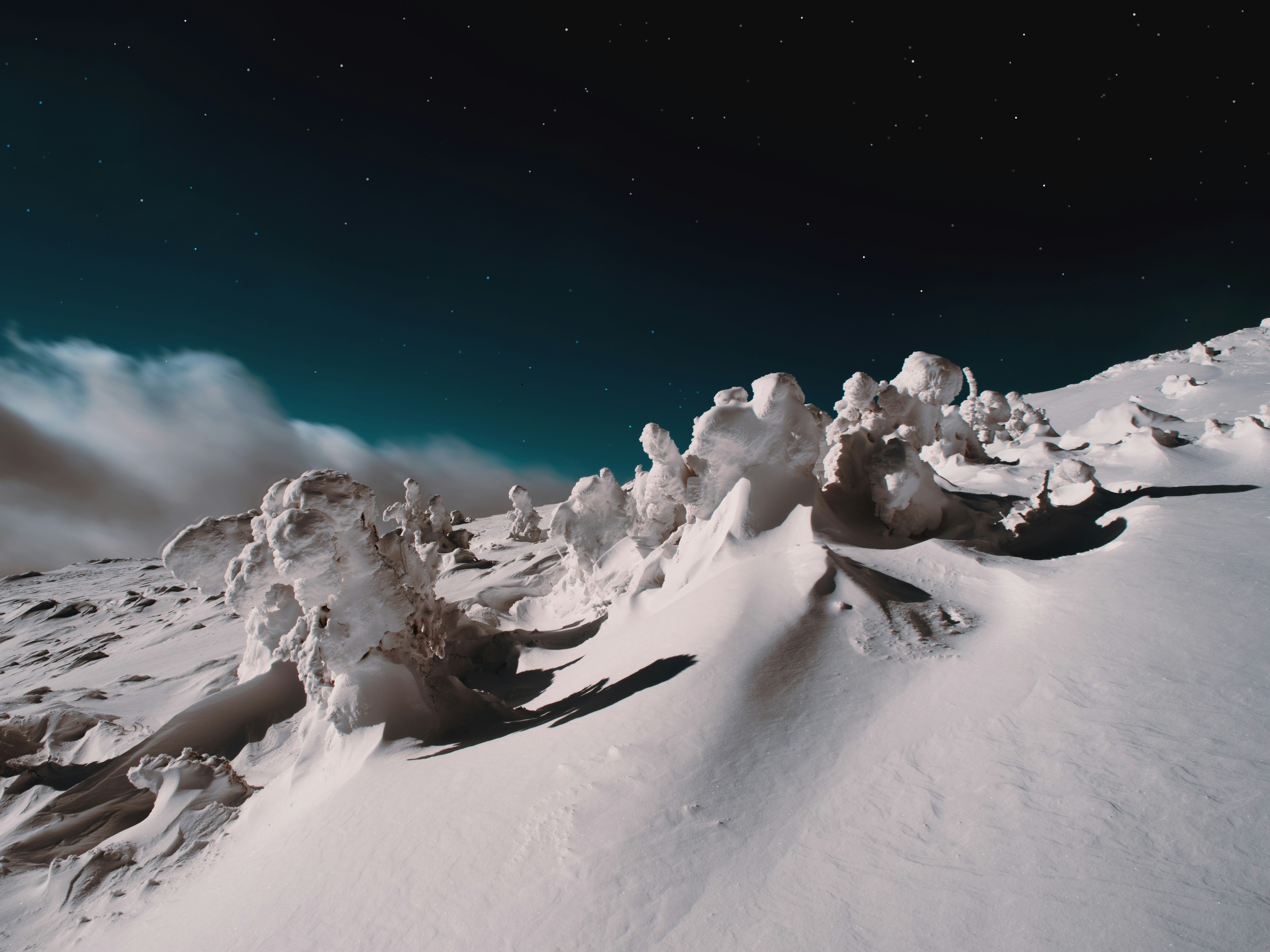 Snow-covered landscape with unique ice formations under a starry sky, creating an otherworldly atmosphere.