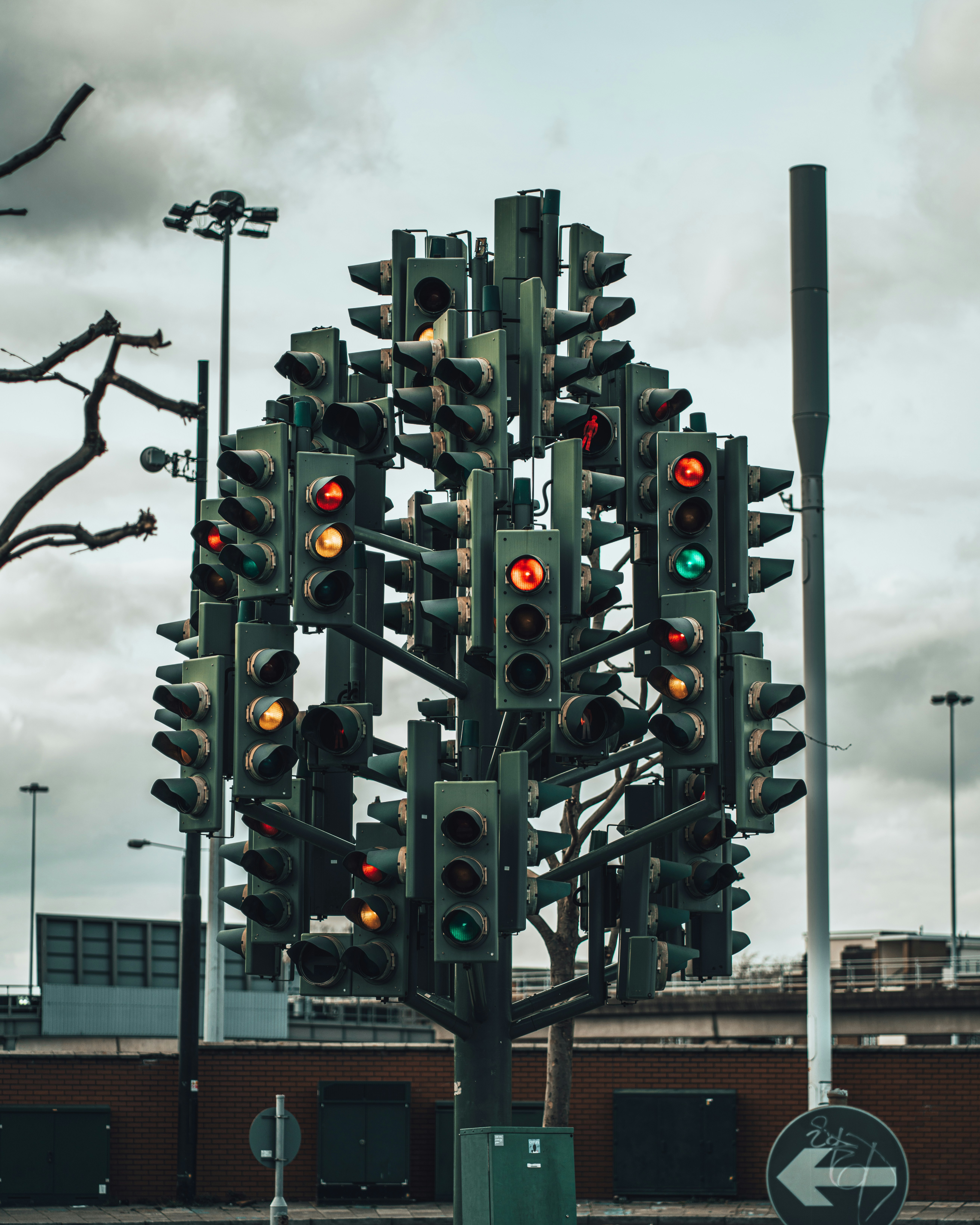 A unique traffic light installation resembling a tree, showcasing a multitude of signals in various states. The scene captures an intriguing interplay of urban design and functionality.