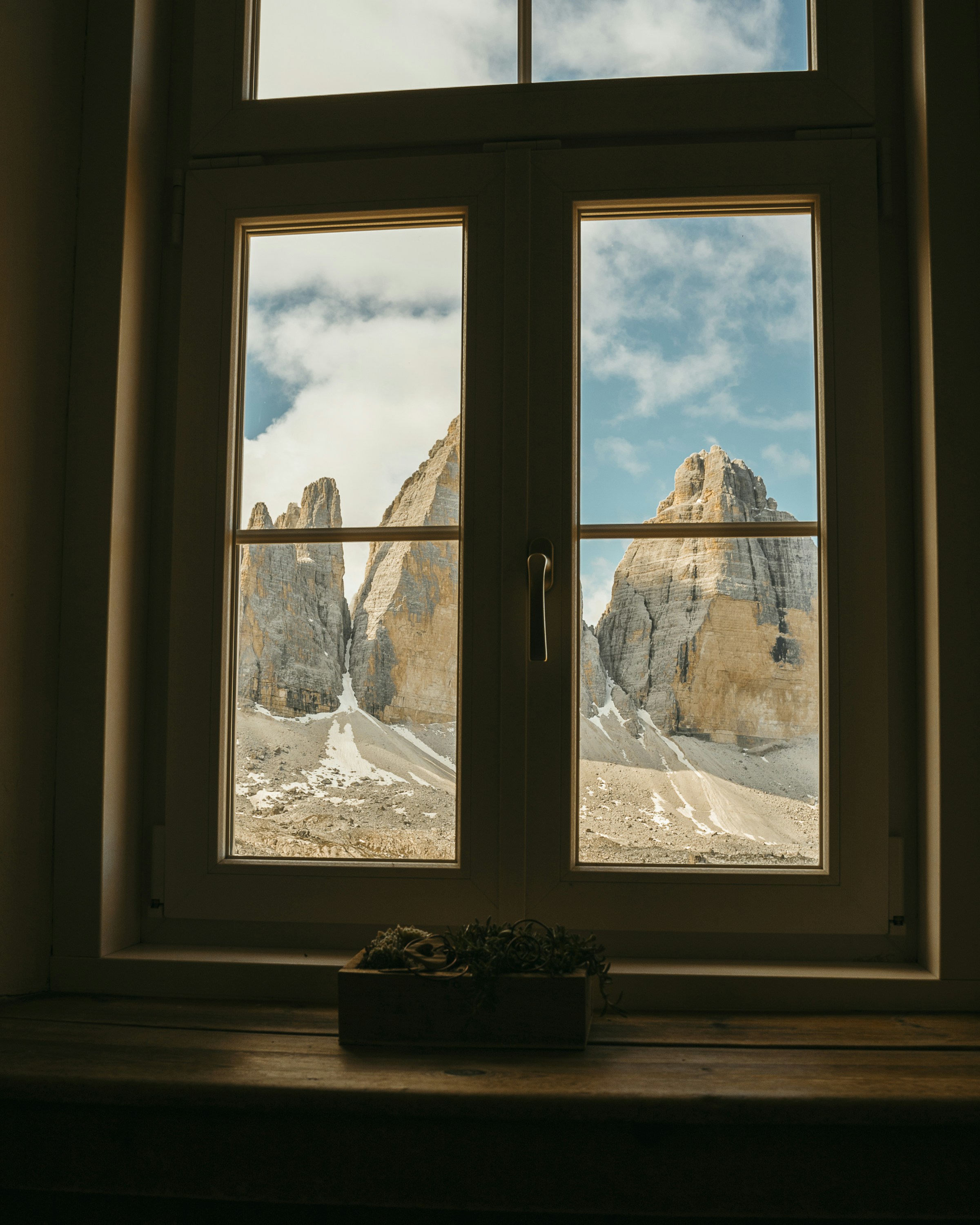 Morning Light Framing Jagged Peaks Through a Cabin Window