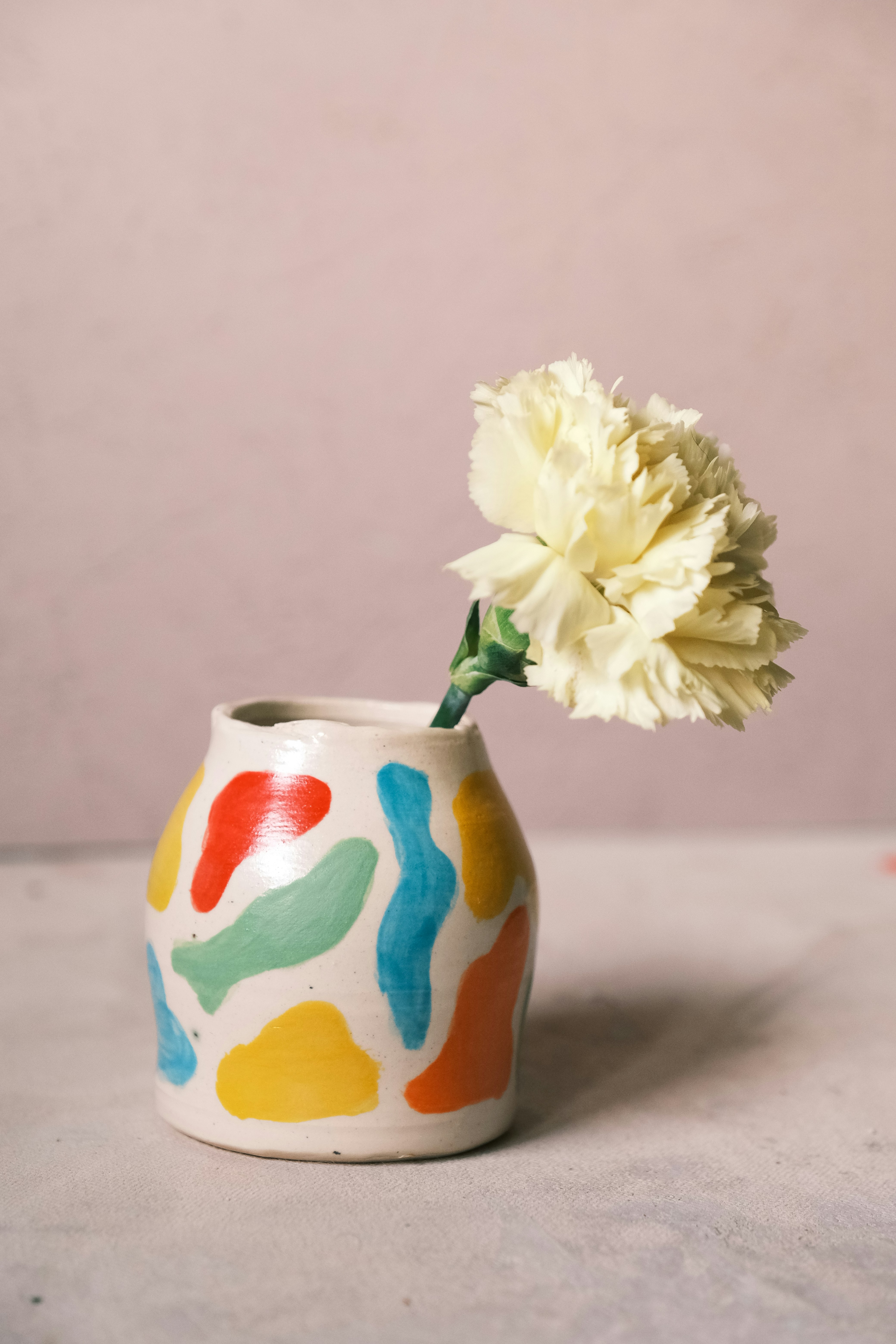 Pastel Vessel: A Cream Carnation in a Colorful Ceramic Cup