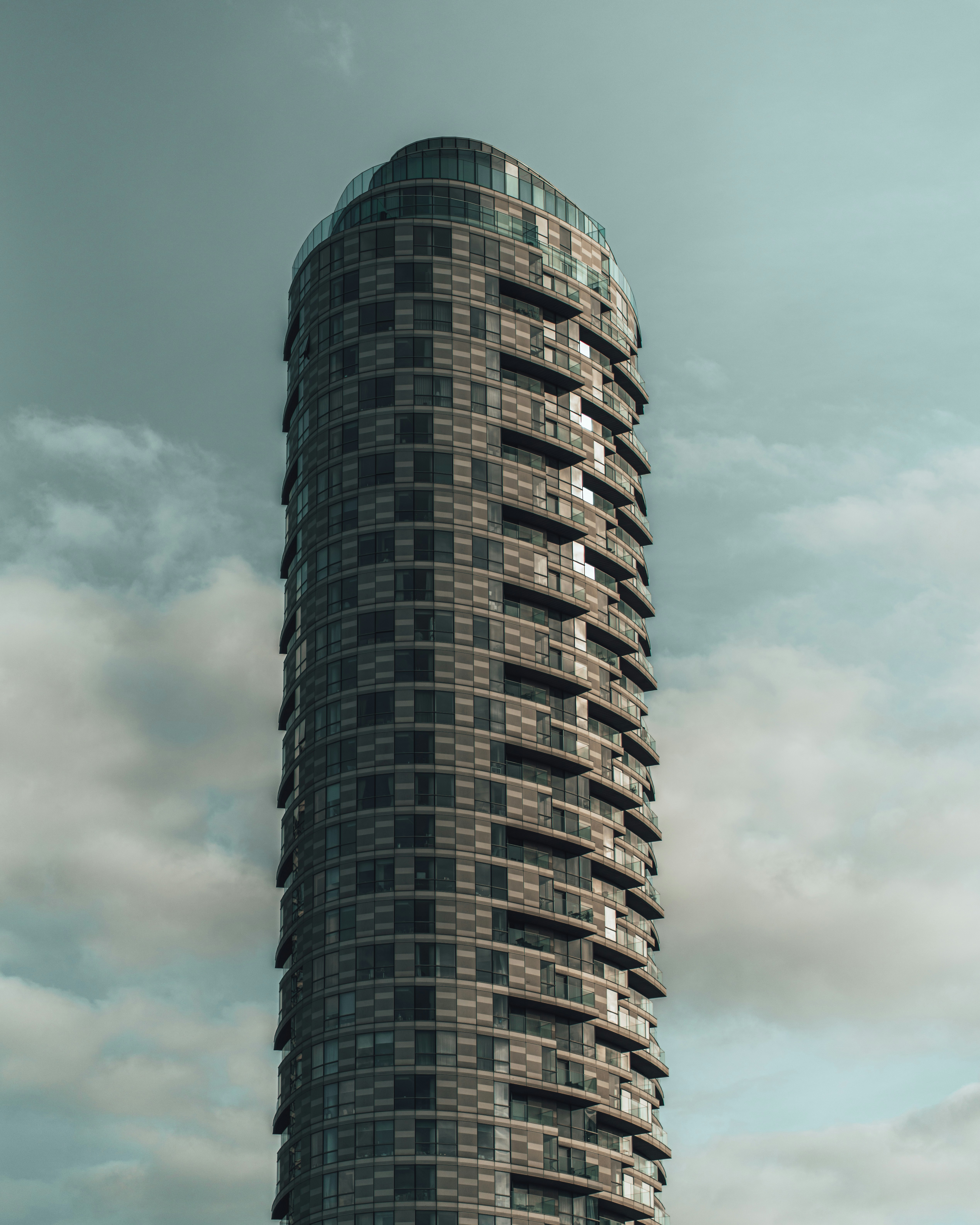 Sleek high-rise building with a unique spiral design against a cloudy sky. Architectural features highlight modern urban aesthetics.