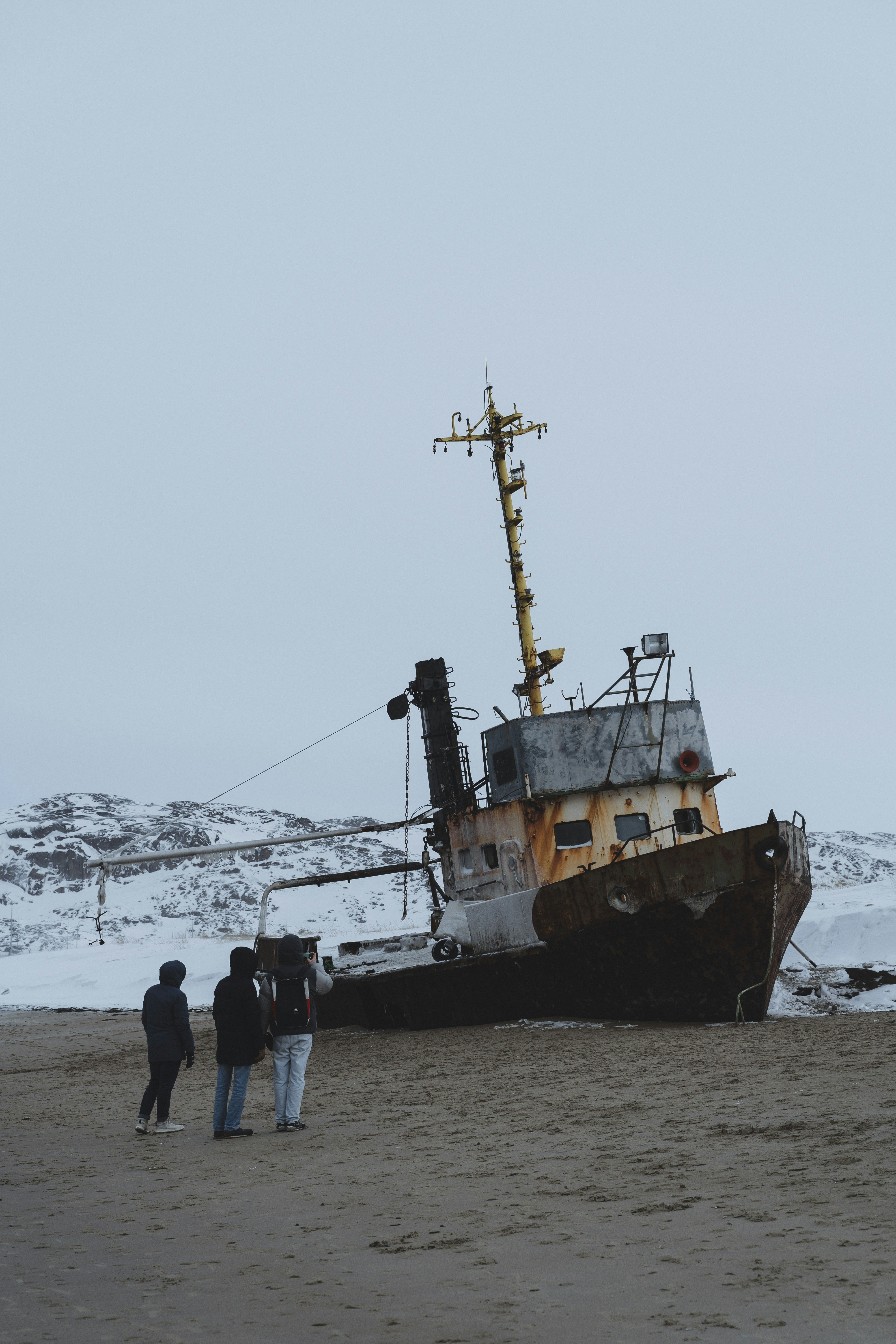 people standing on beach shore near brown ship during daytime