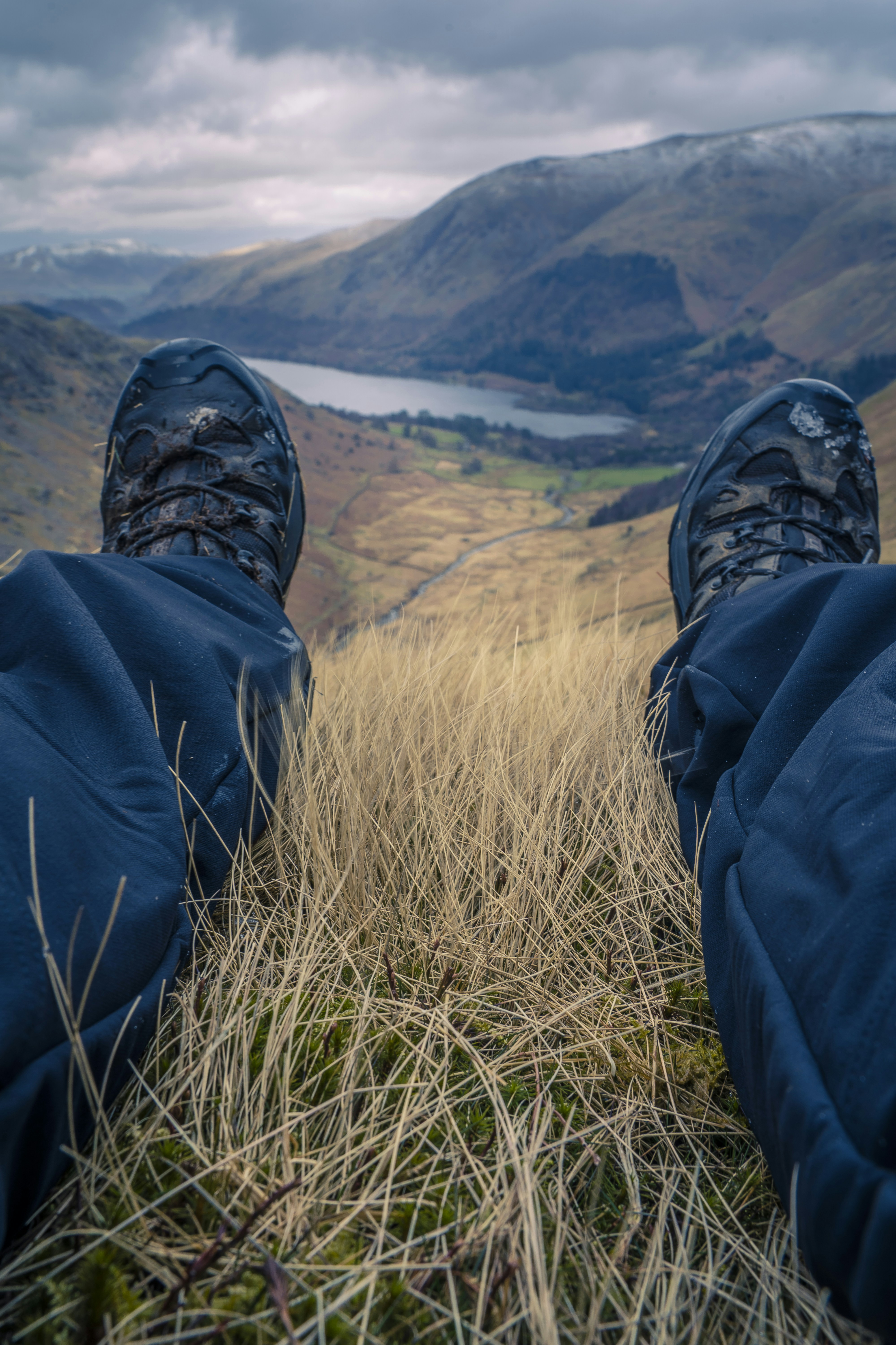 Ridge-Edge Reverie: Boots Framing a Quiet Valley and Lake Below