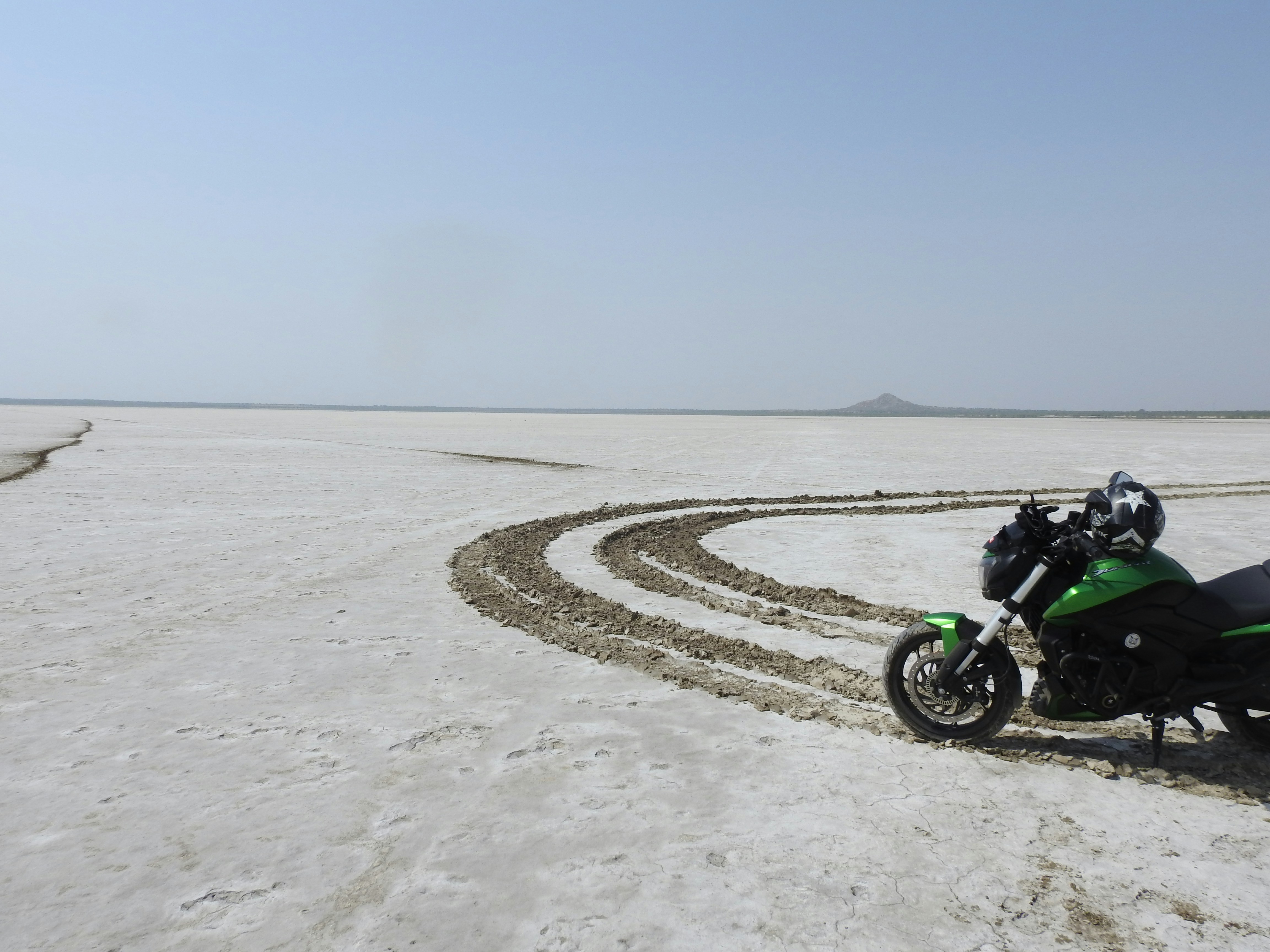 Green sport motorcycle carves a curved path across the salt-flat