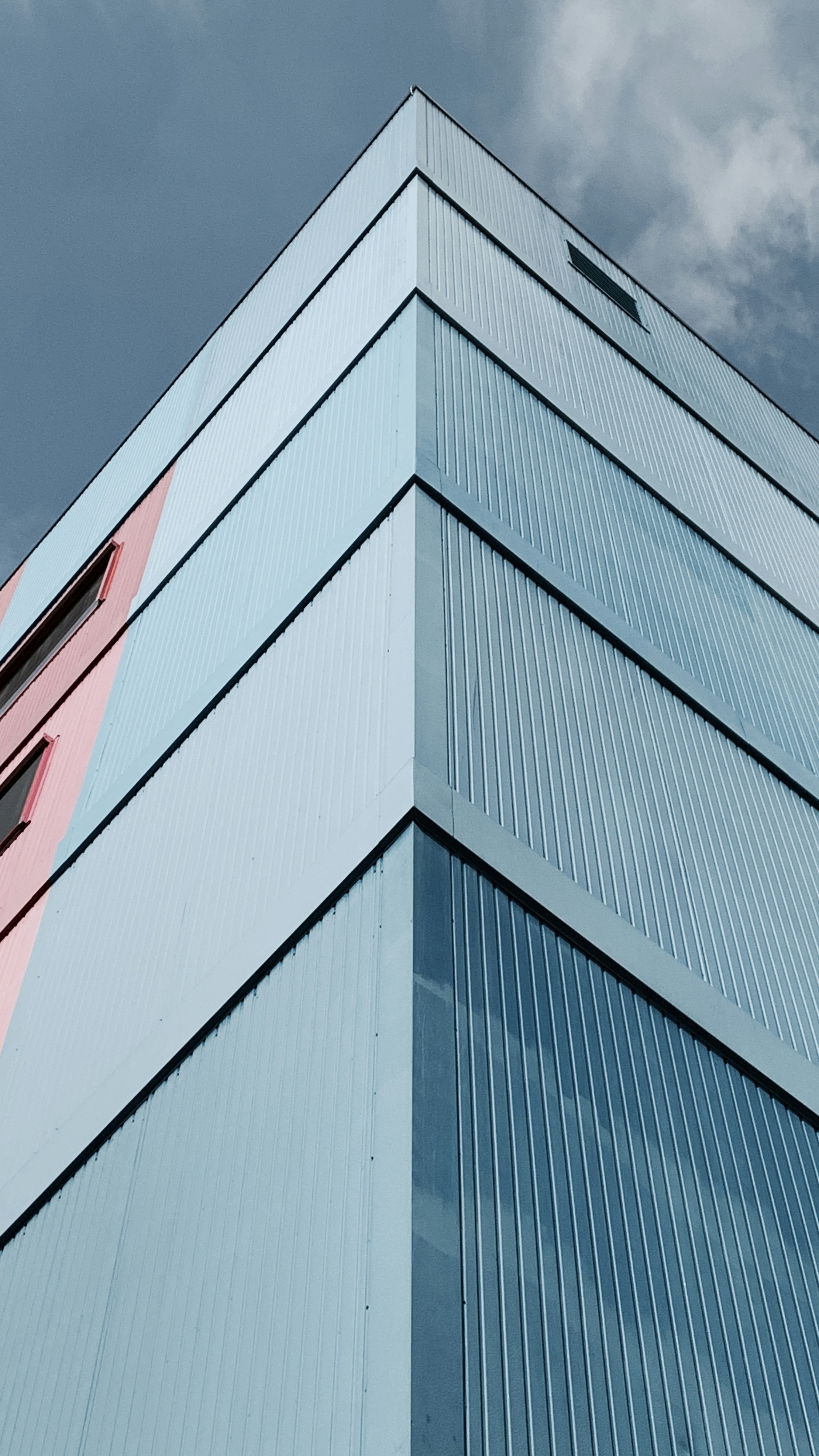 Vibrant building facade showcasing sharp angles and contrasting colors against a cloudy sky.