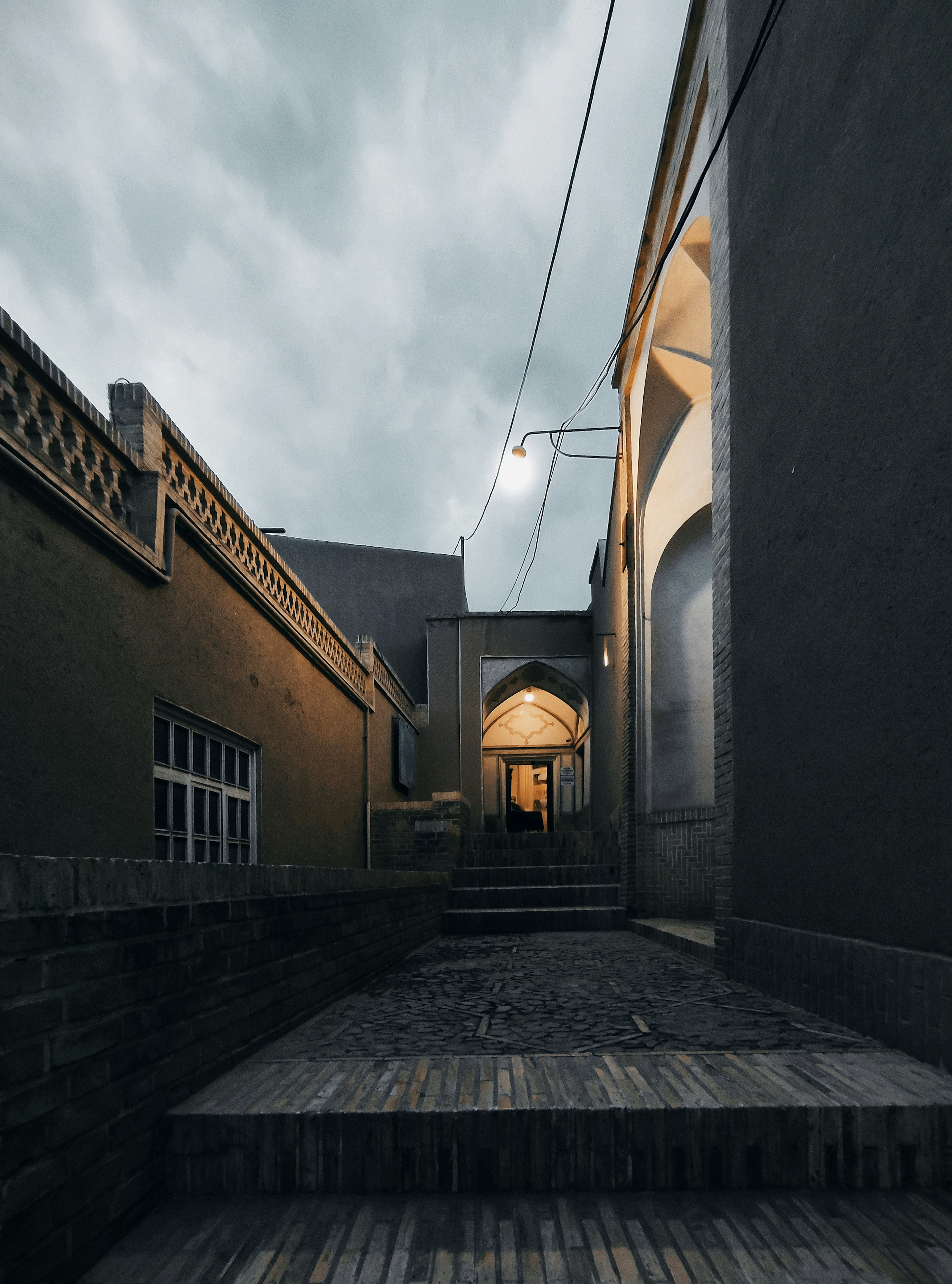 Archway Ascent: A Cobblestone Corridor Toward Warm Light