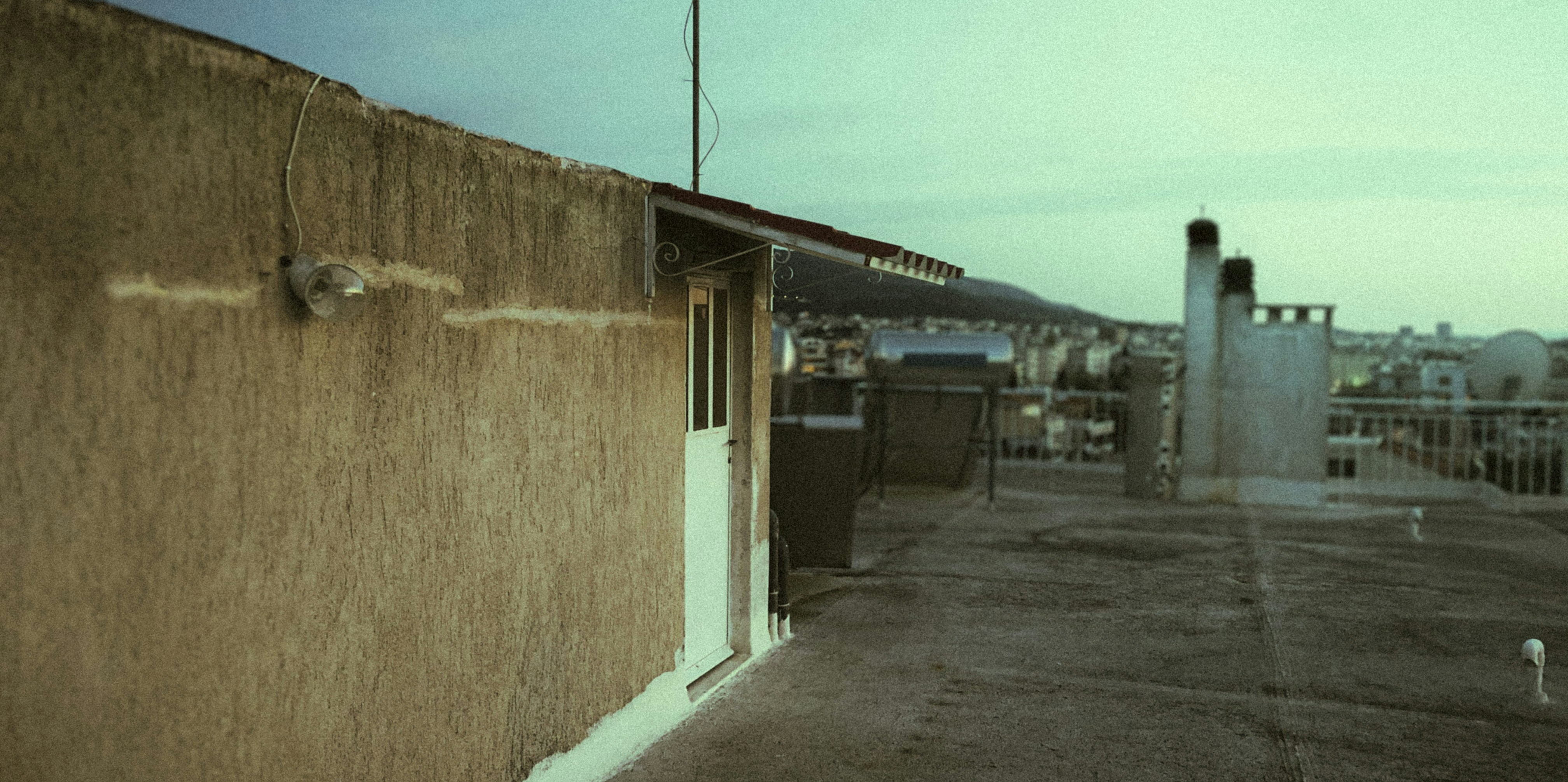 A vintage film-like shot of on a roof of a building. | brown wooden door near brown wooden wall