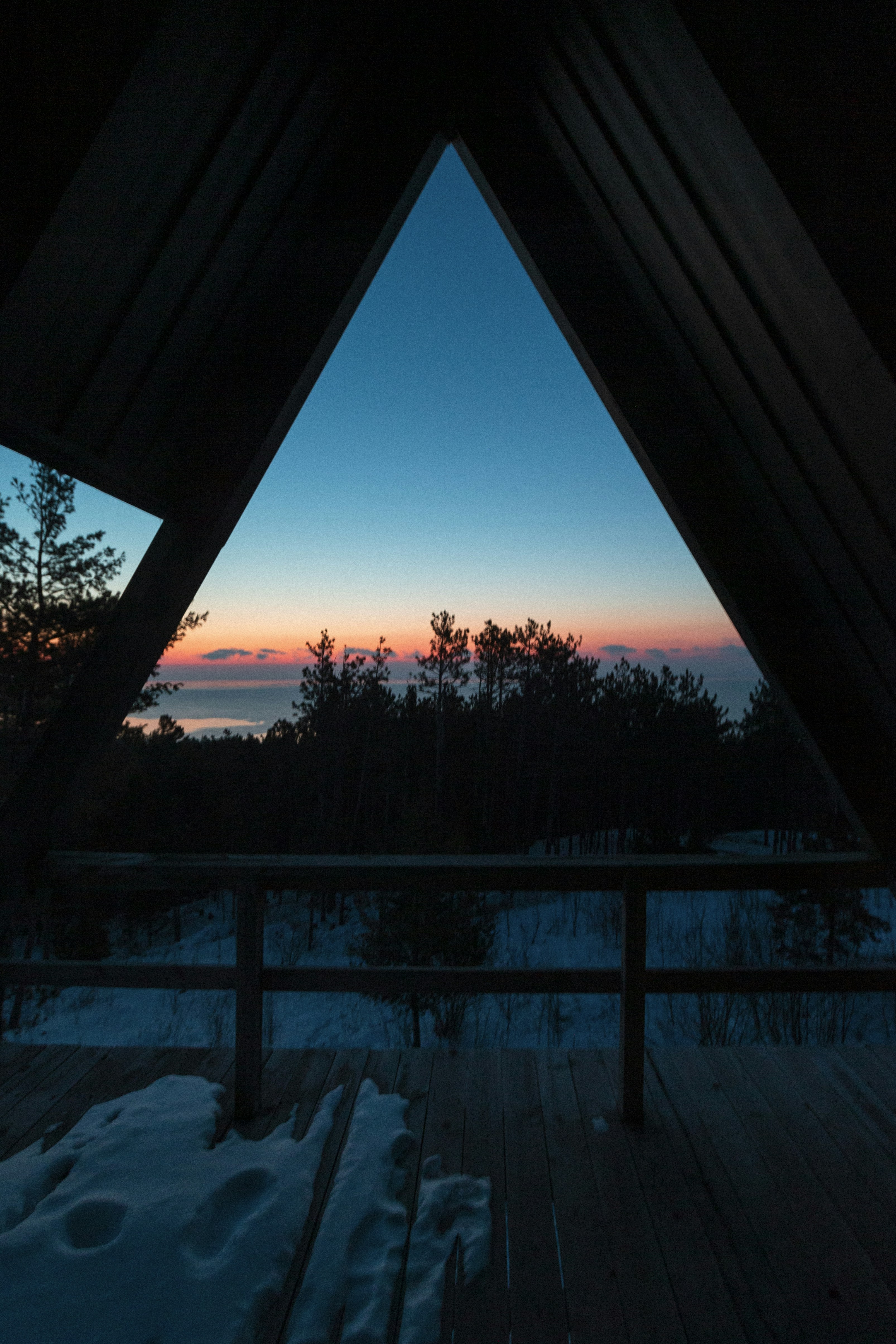 Dusk Framed: Sunset Through an A-Frame Window over Snow and Pines