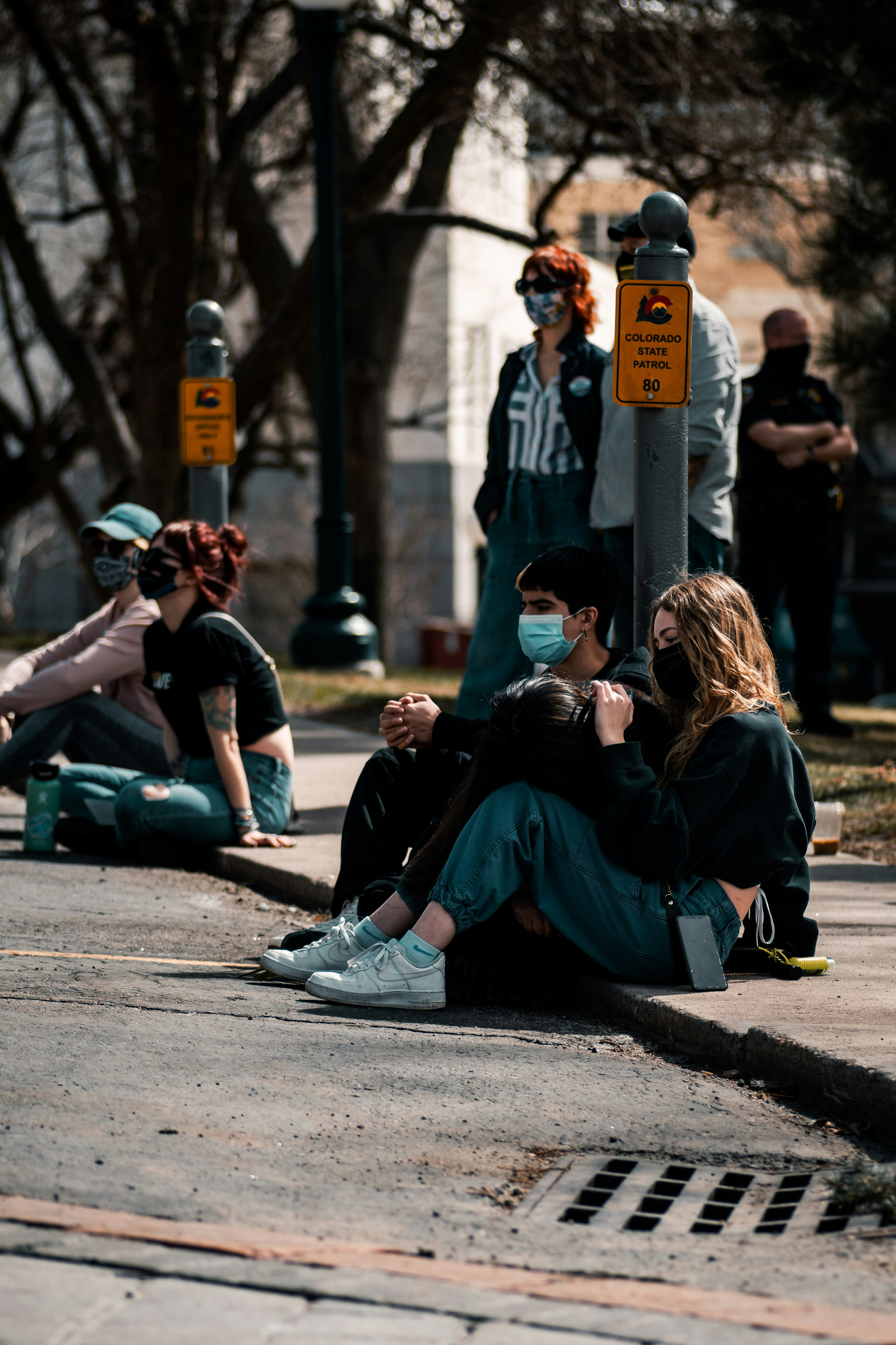Quiet Pause on the City Steps: A Group in Masks Beneath a Park Sign