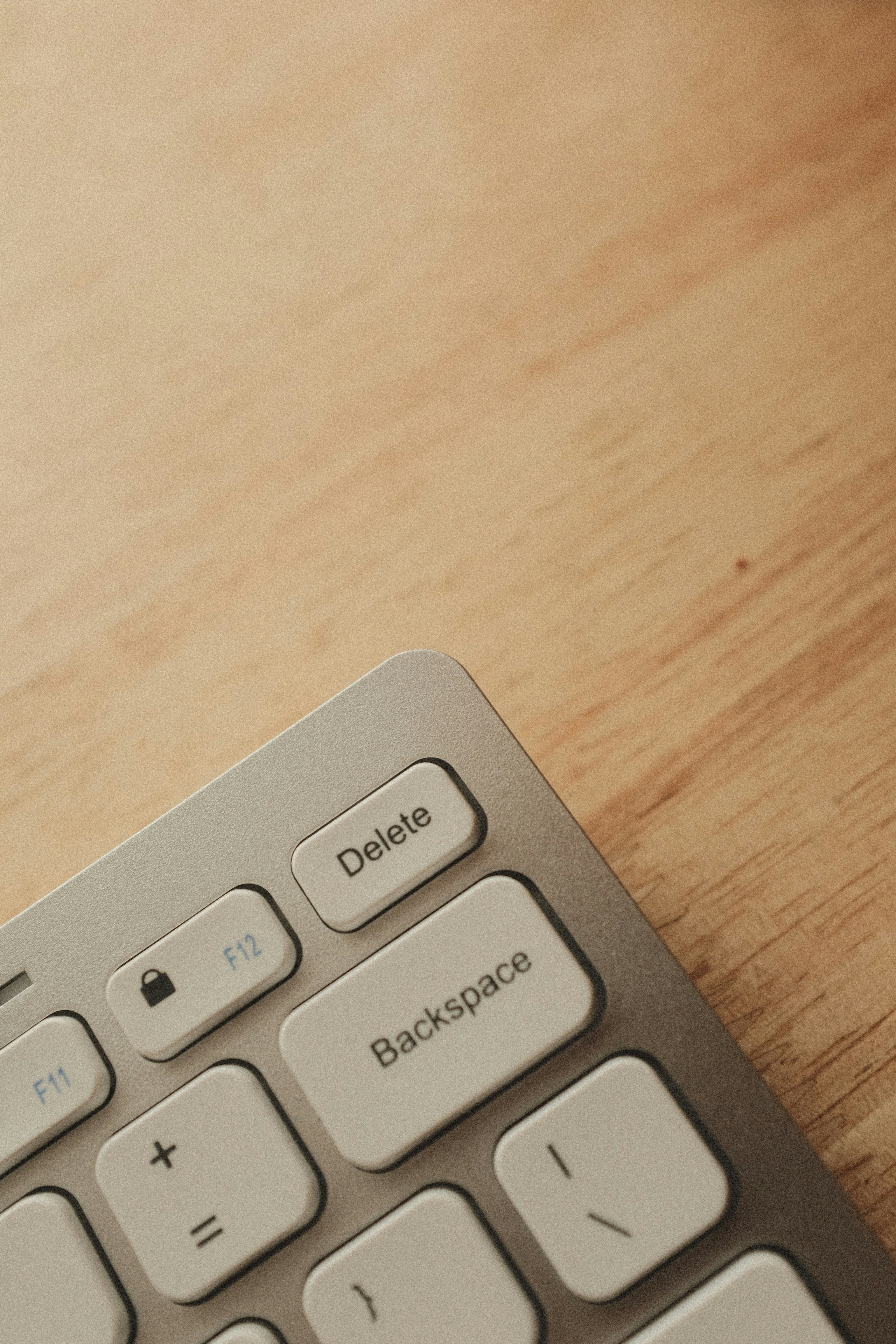 Edge of a Quiet Keyboard: Close-Up of Delete and Backspace on Warm Wood