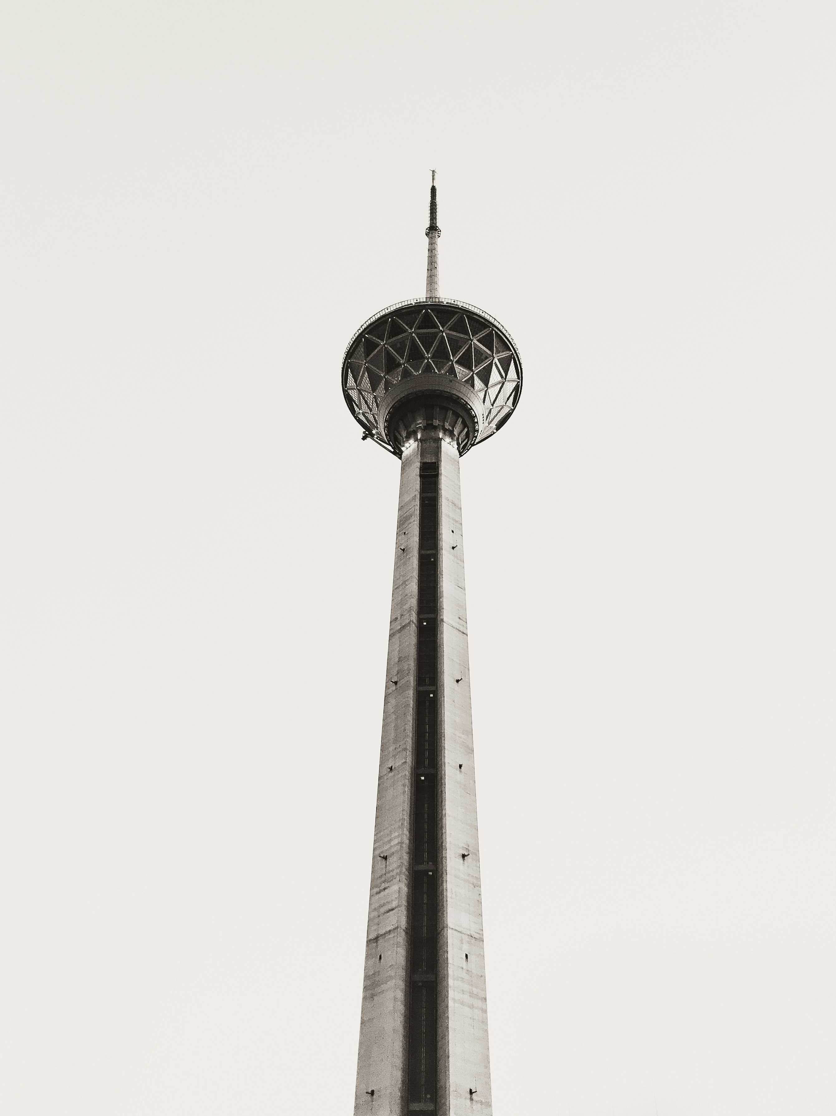 A tall telecommunications tower reaching into the sky, showcasing a geometric design and minimalist aesthetic.