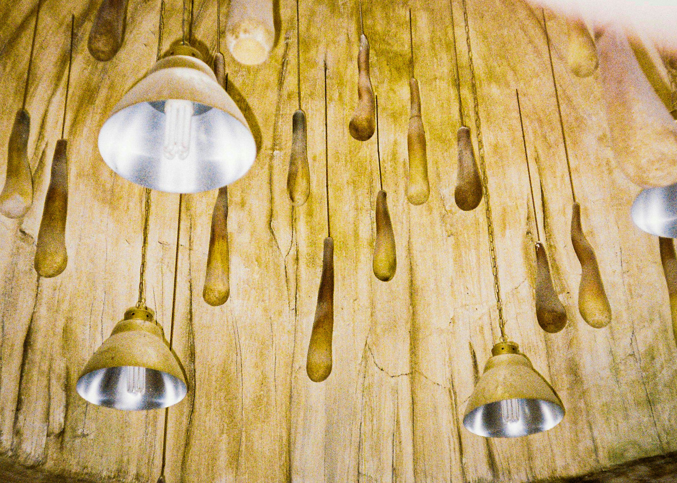 Unique ceiling arrangement featuring hanging light fixtures and wooden elements, creating an artistic interplay of light and shadow.